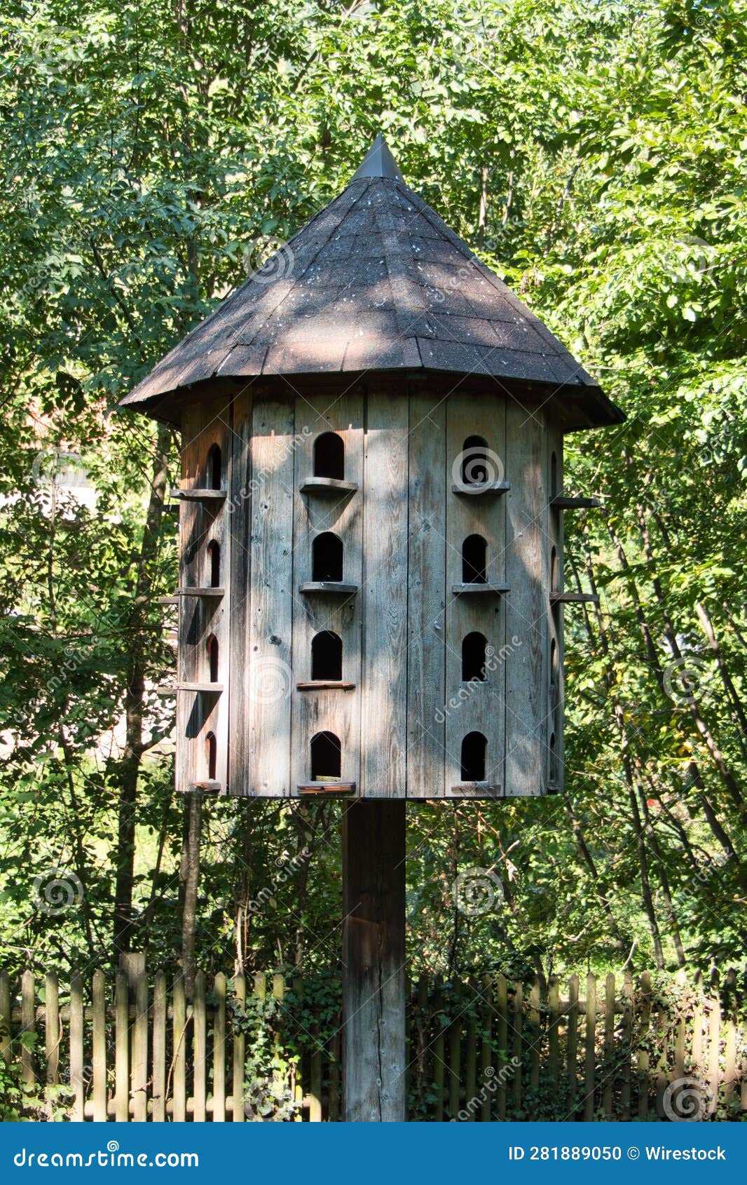 Wooden Birdhouse Situated To the Side of a Picket Fence, with a Tree ... Wooden Birdhouse Situated To the Side of a Picket Fence, with a Tree ...