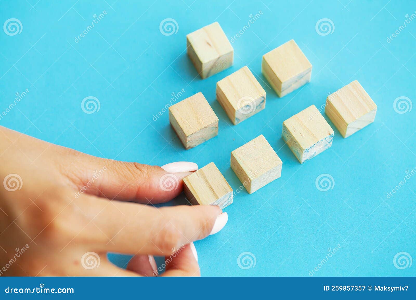 Wooden Blocks with a Human Hand Placing One Cube at the Top on Blue ...