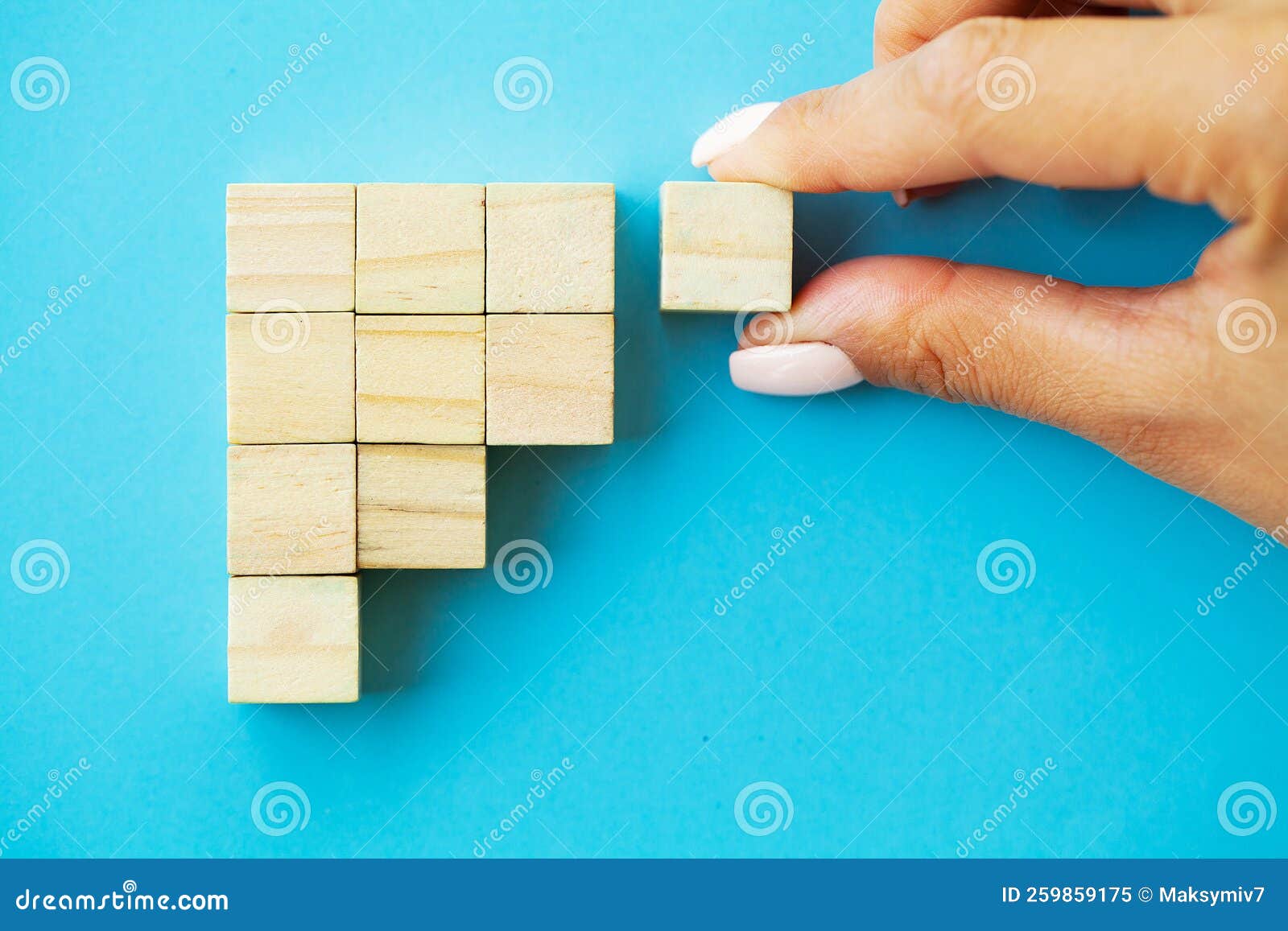 Wooden Blocks with a Human Hand Placing One Cube at the Top on Blue ...