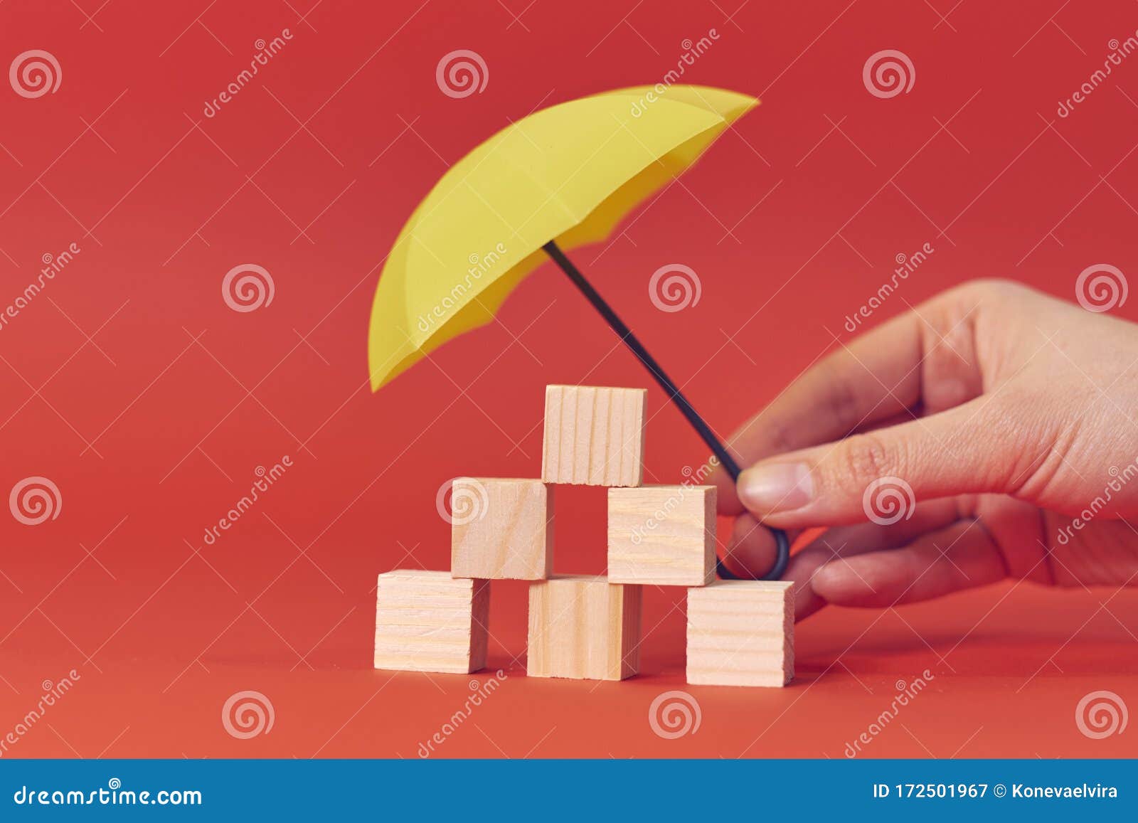Wooden Blocks Under Umbrella on Table Against Red Background Stock ...
