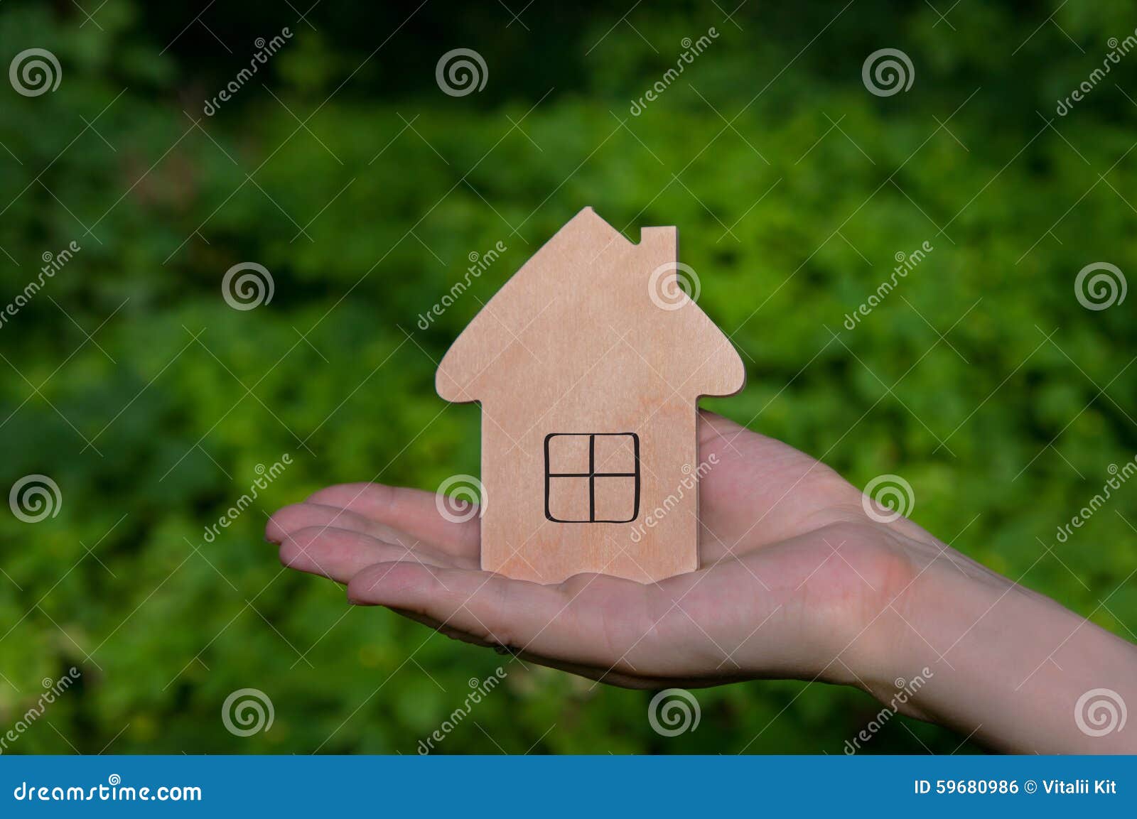 Wooden House on the Hand on Green Background Stock Photo - Image of ...