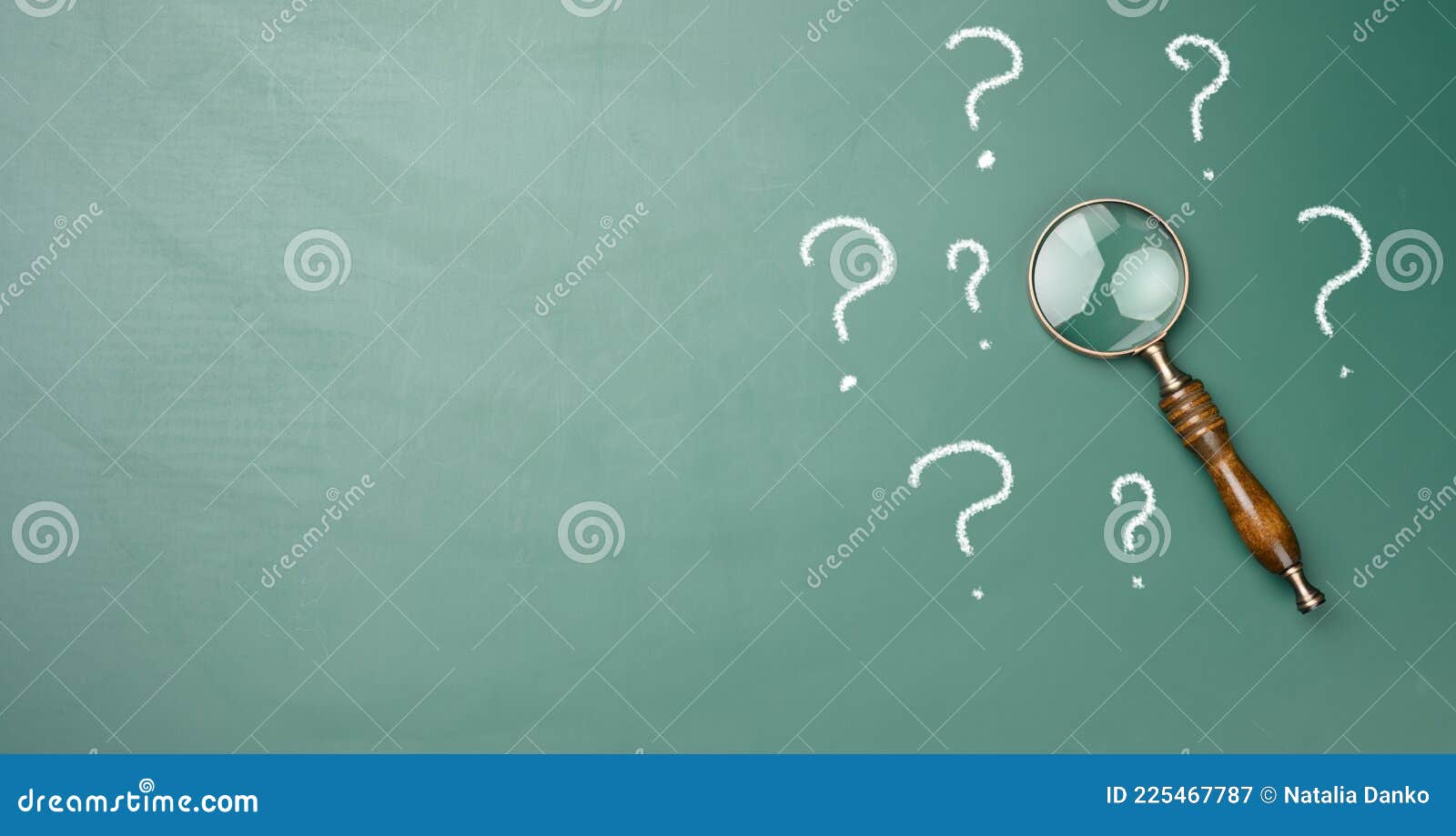 Wooden Magnifying Glass and White Chalk Drawn Question Marks on a Green ...