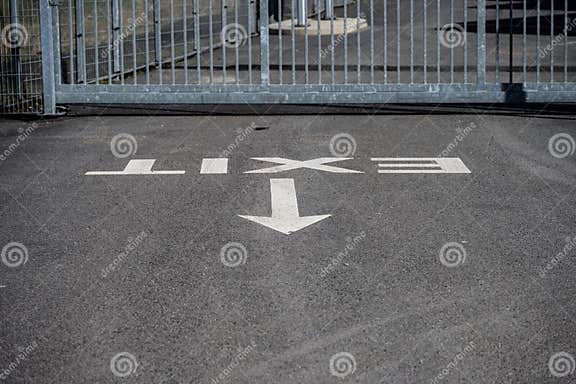 Word Exit and Arrow Painted on Asphalt by a Gate.. Stock Image - Image ...