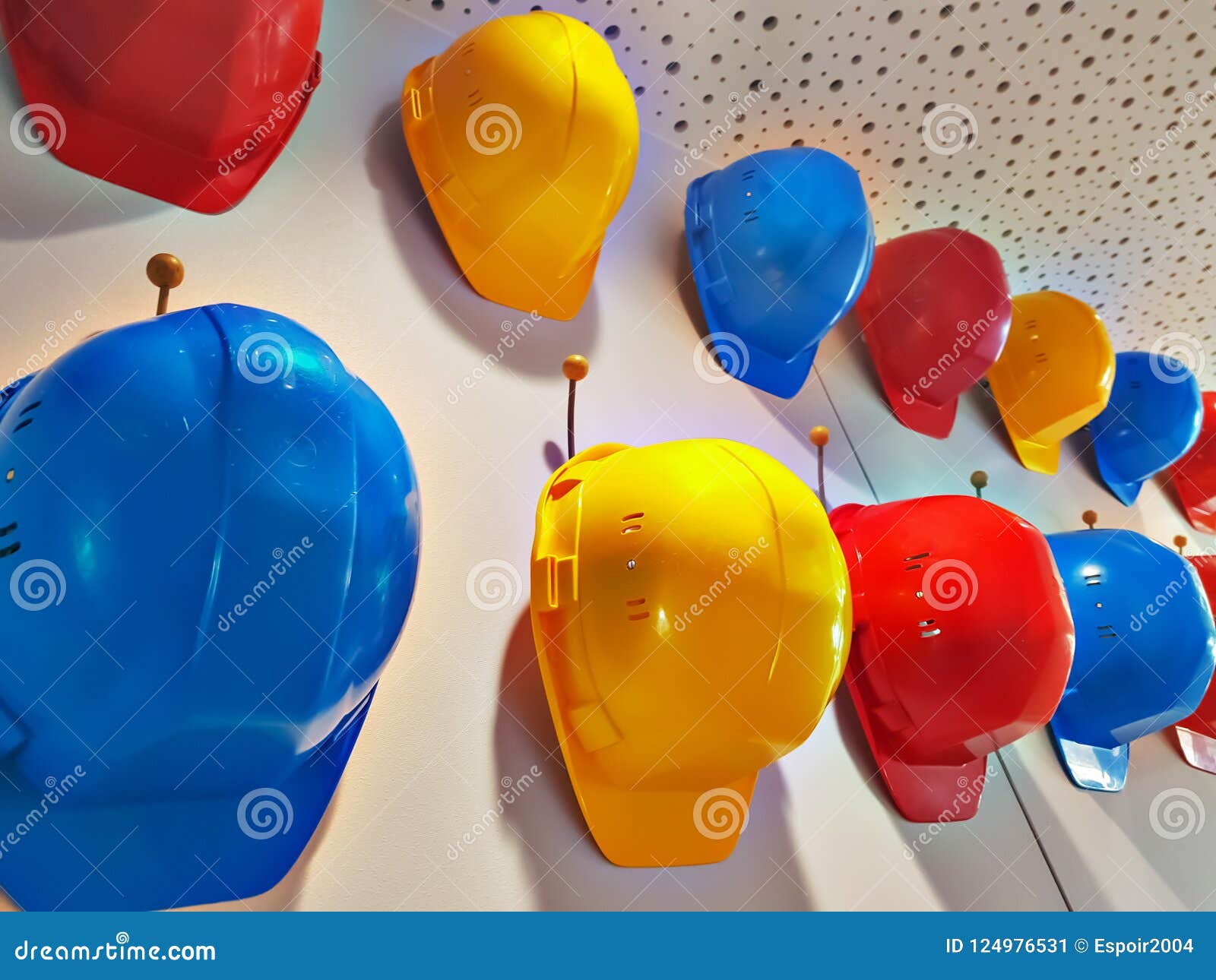 Work Helmets of Different Colors Hang on Hooks on the Wall. Stock Image ...