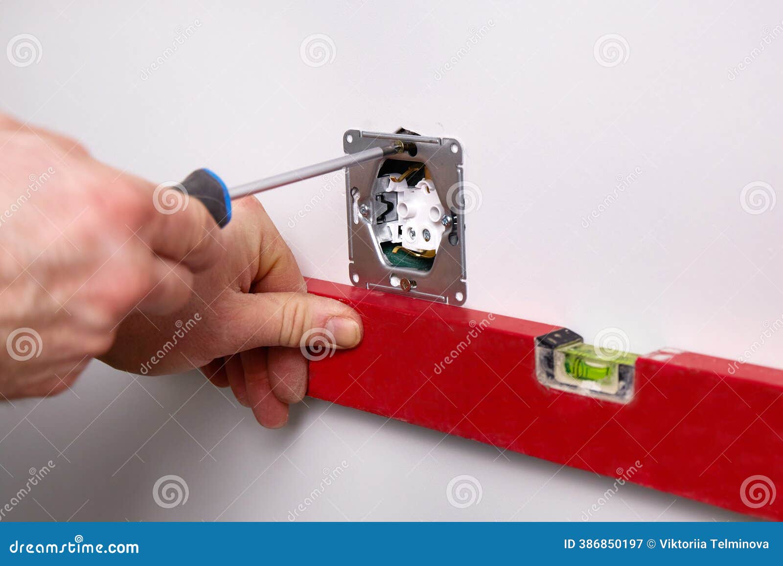 An Electrician Uses A Red Screwdriver To Screw A Double Grounded ...