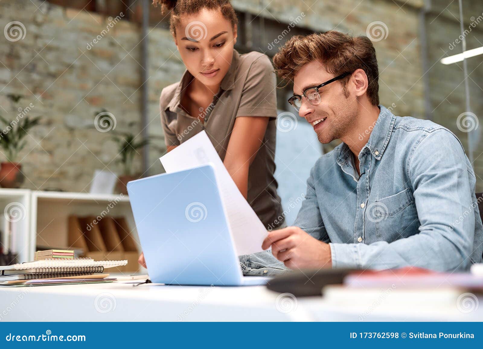 Work in Progress. Young Colleagues Looking at Document and Discussing ...