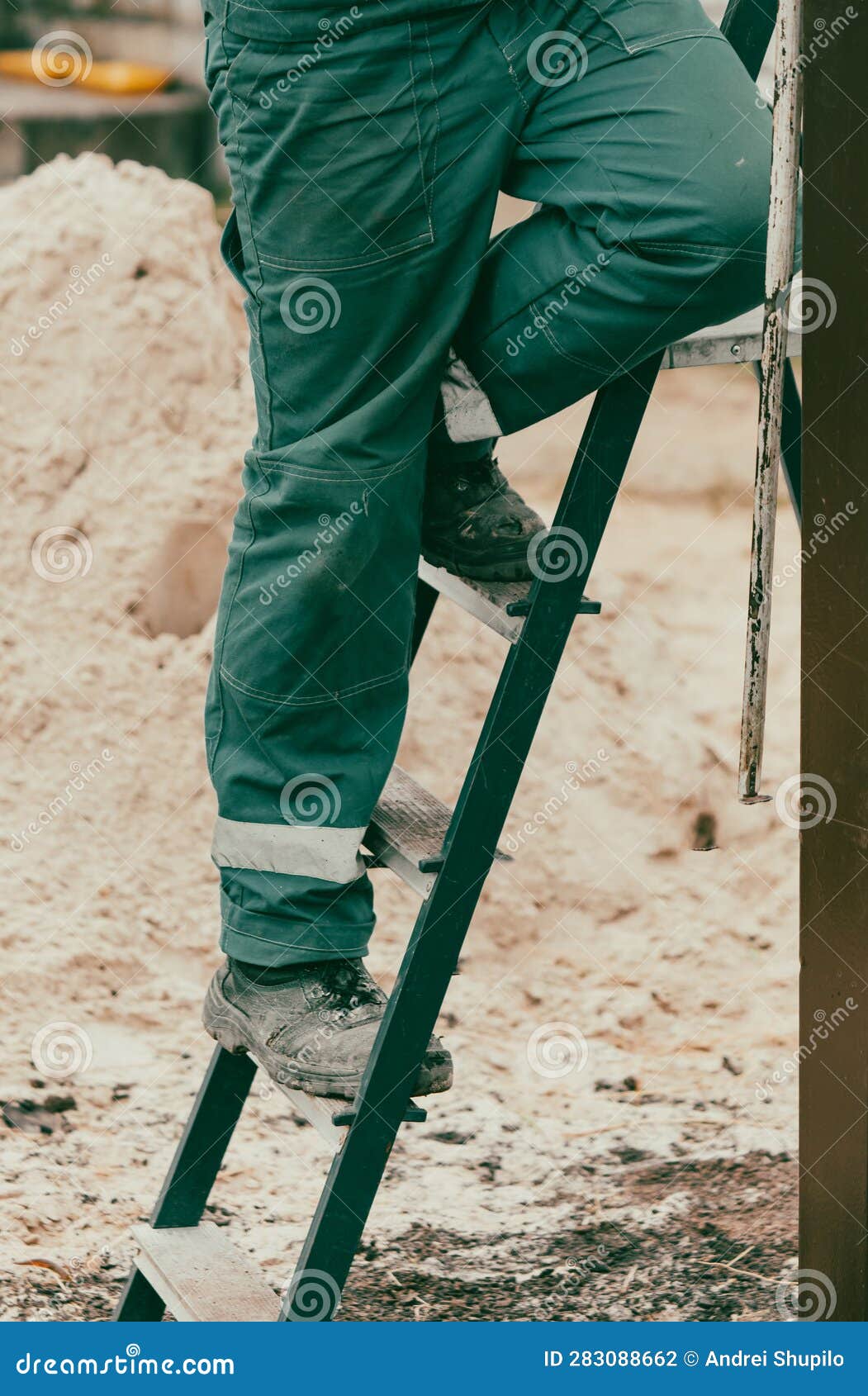 Worker in Blue Overalls Stands on a Metal Ladder in the Yard Stock ...