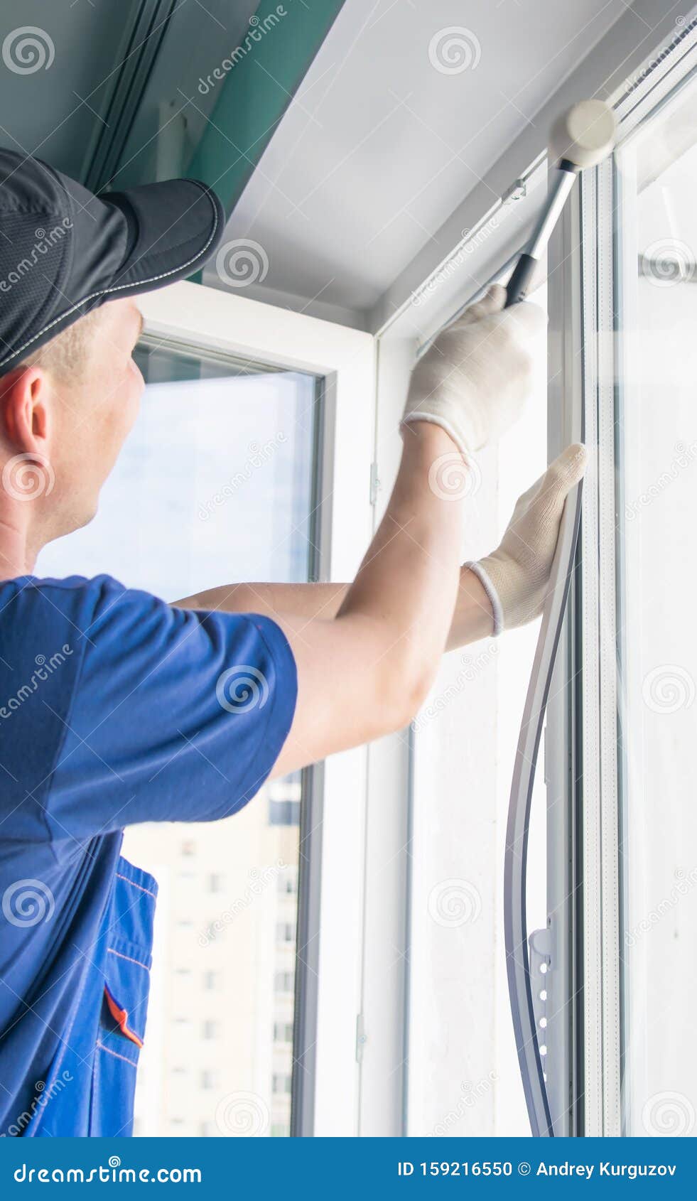 A Worker in a Blue Uniform Installs a Double-glazed Window in a Plastic ...