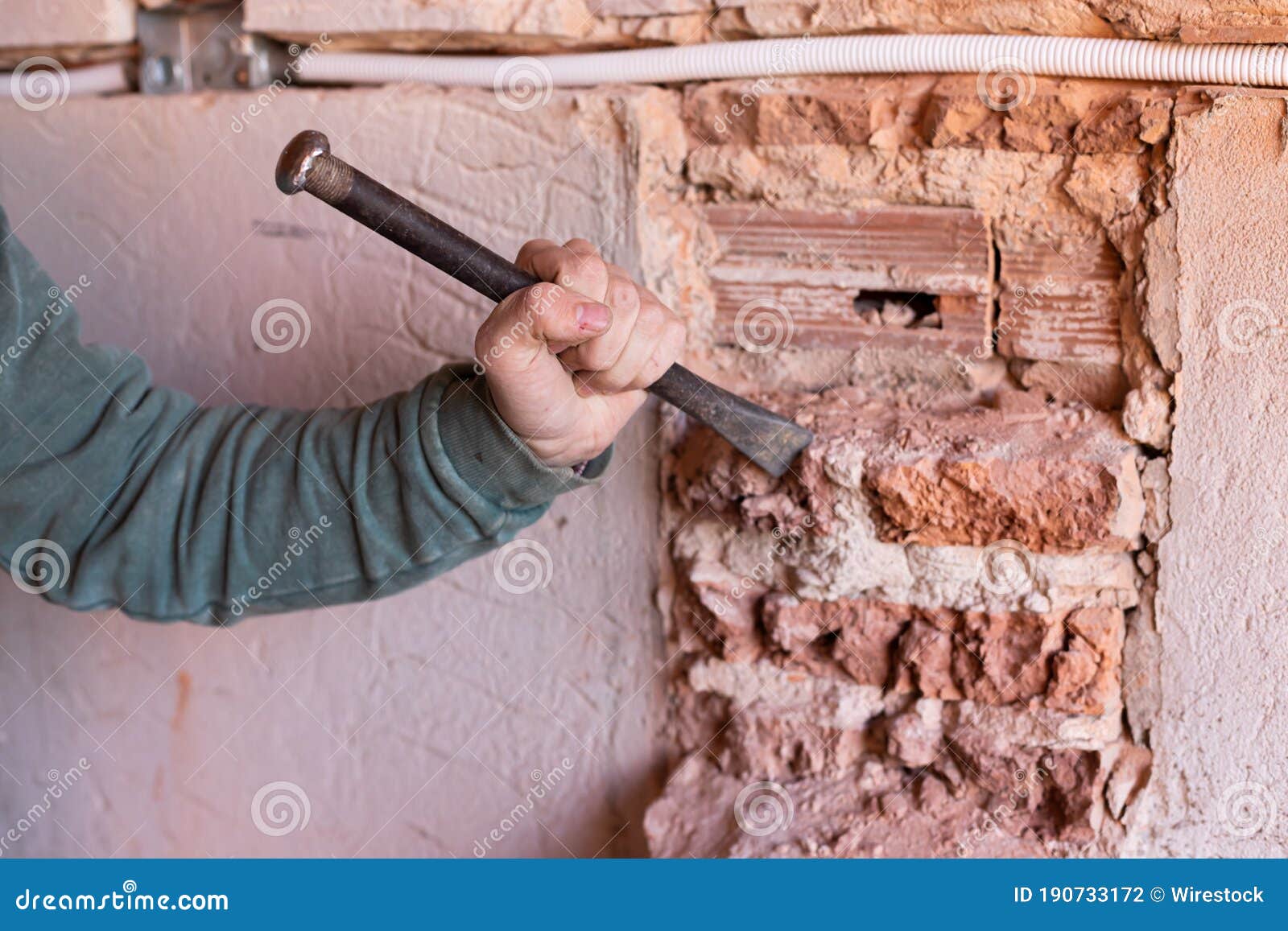 Worker Breaking the Wall with Hammer and Chisel in a Construction Site ...