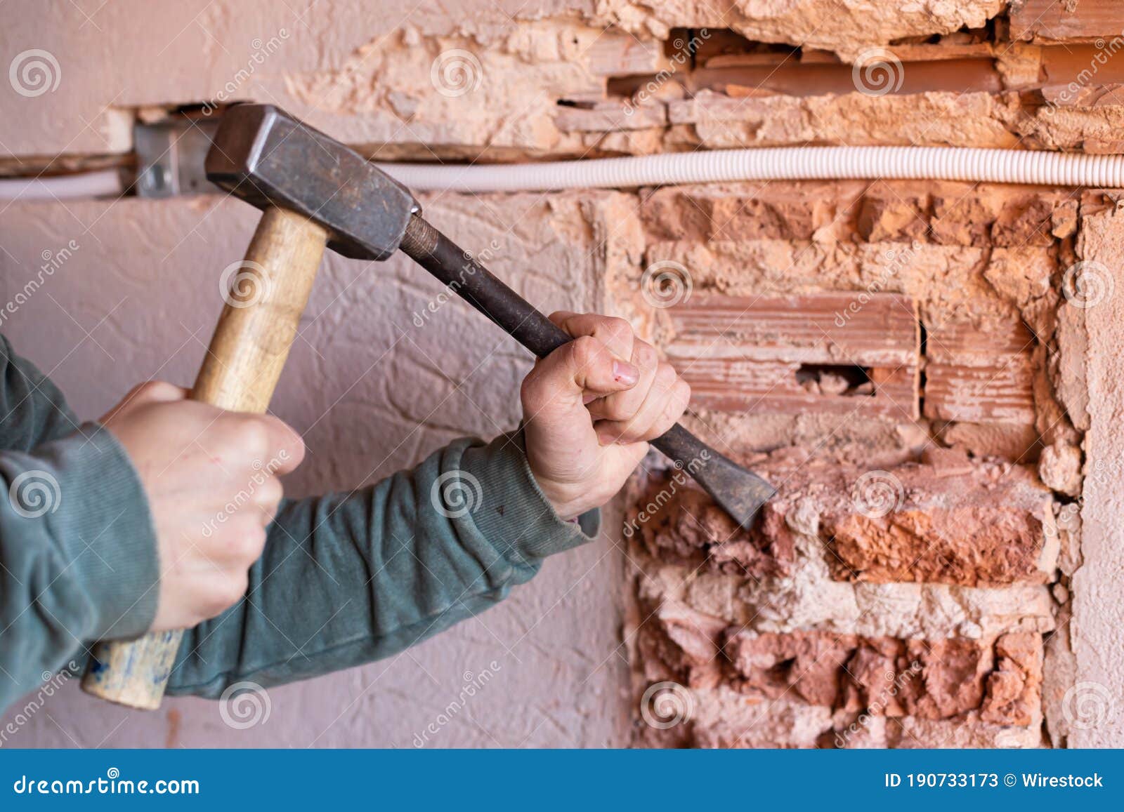 Worker Breaking the Wall with Hammer and Chisel in a Construction Site ...