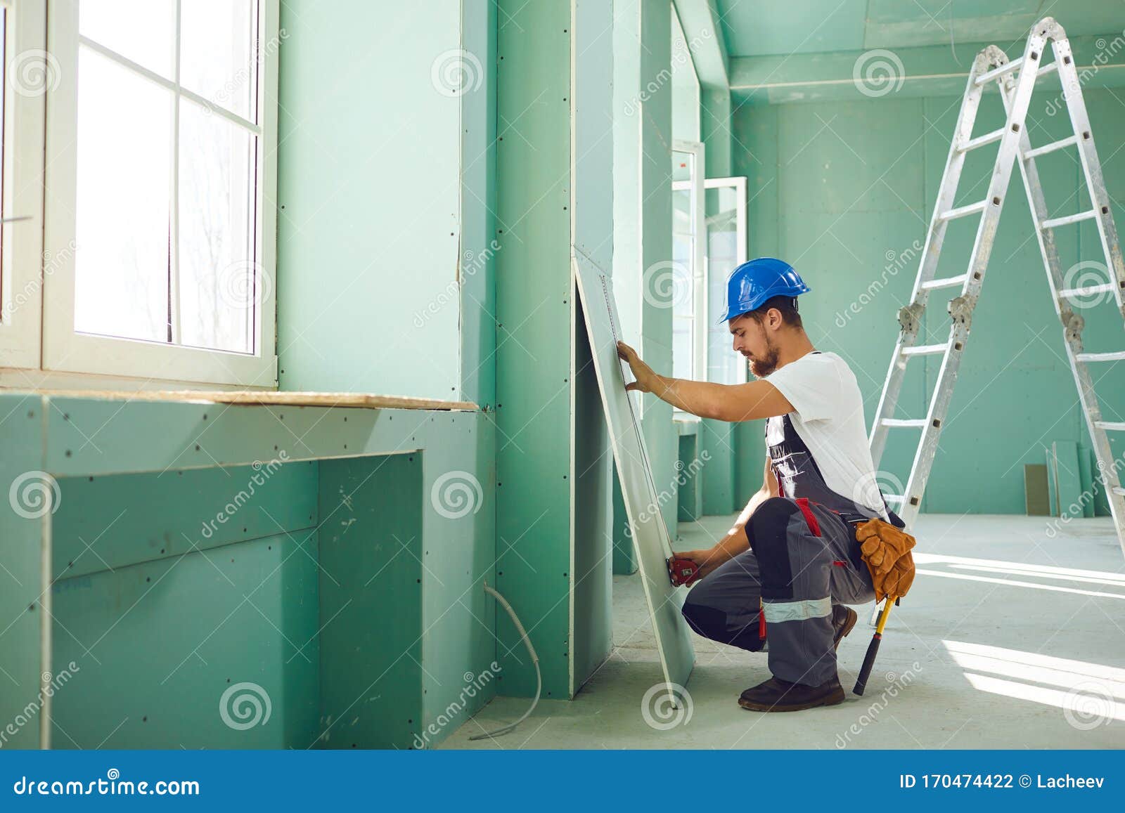 Worker Builder Installs Plasterboard Drywall at a Construction Stock ...