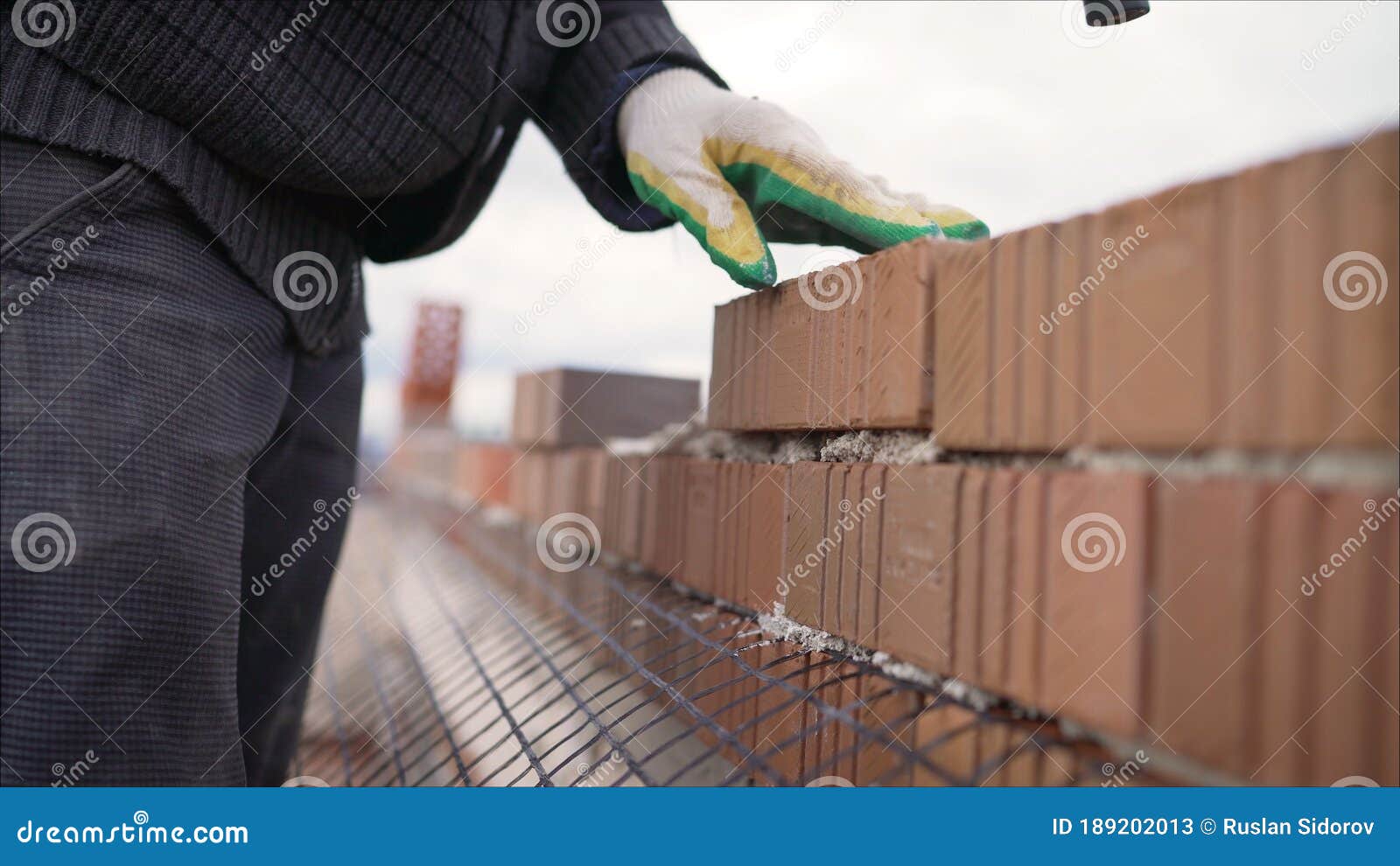 Worker Builds a Wall of Colored Brick. Worker in Close Up of Industrial ...