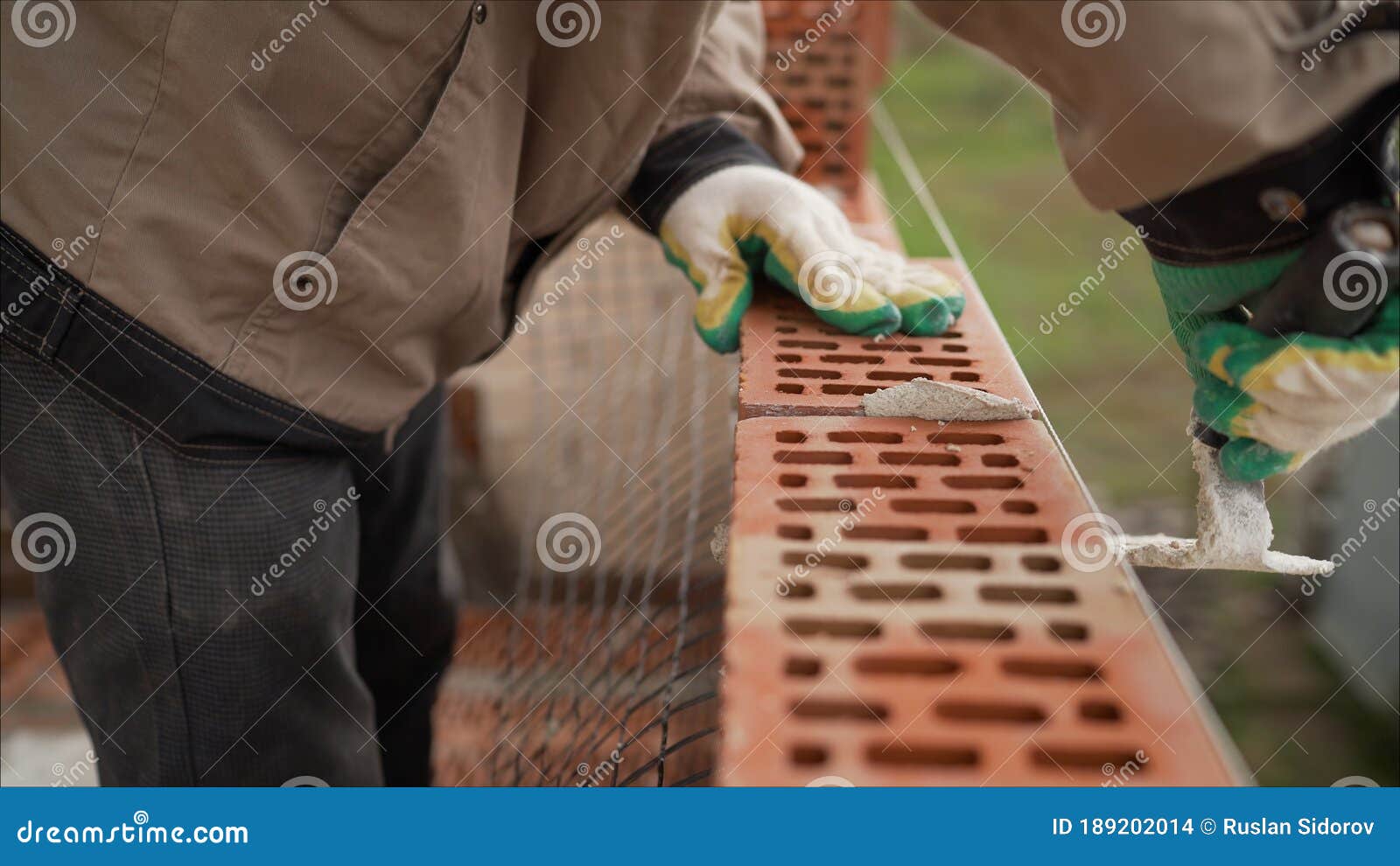 Worker Builds a Wall of Colored Brick. Worker in Close Up of Industrial ...