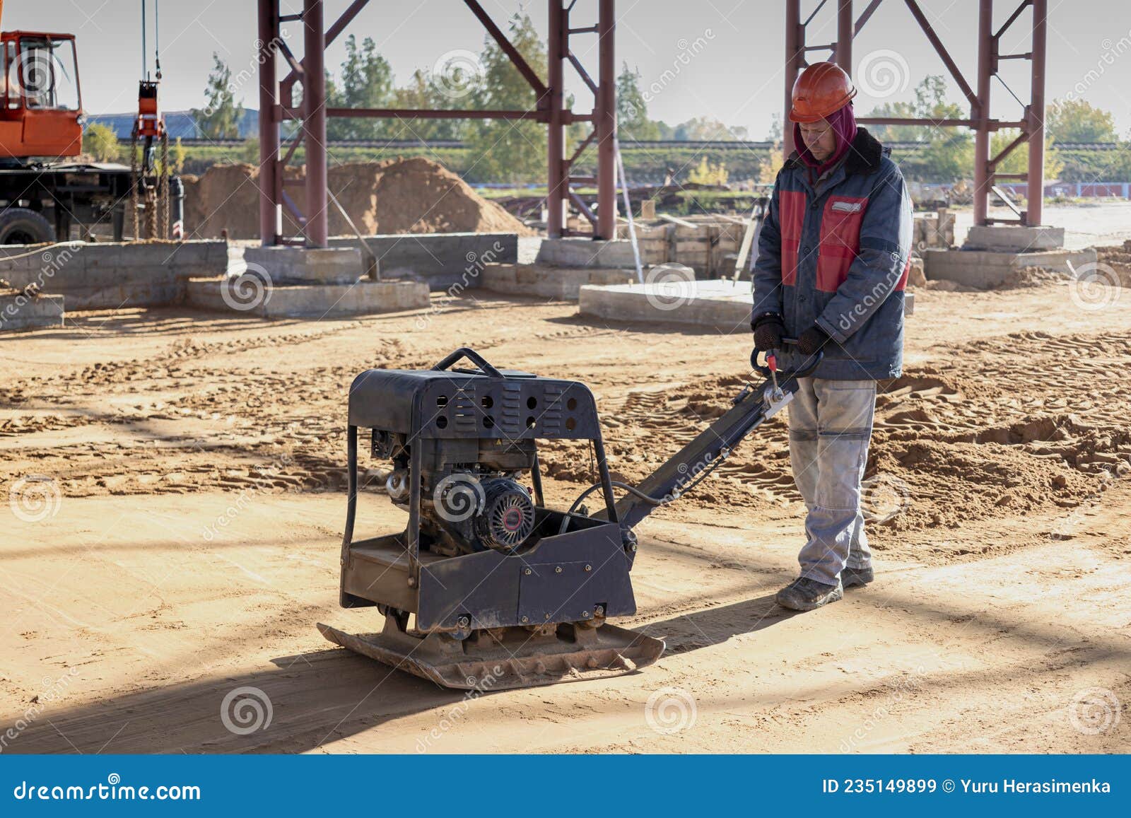 A Worker Compacts Soil Or Sand With A Vibrating Plate In A Trench At A ...
