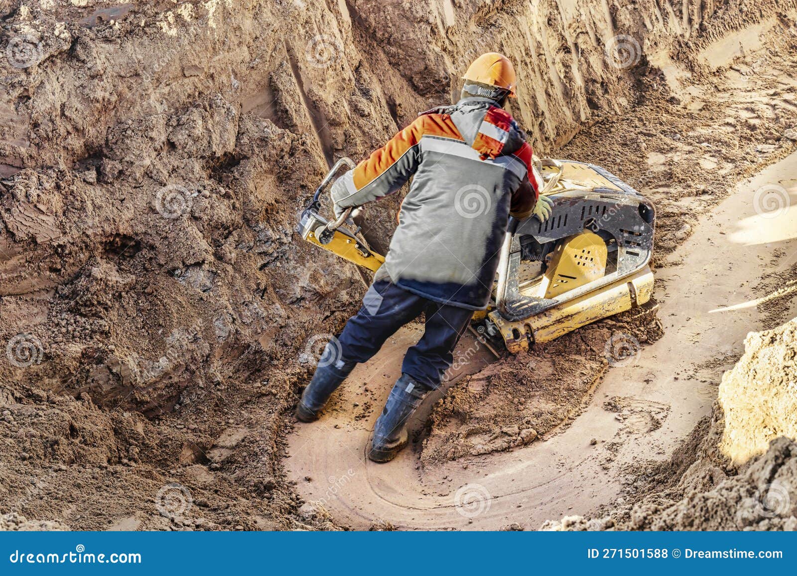 A Worker Compacts Soil or Sand with a Vibrating Plate in a Trench at a ...