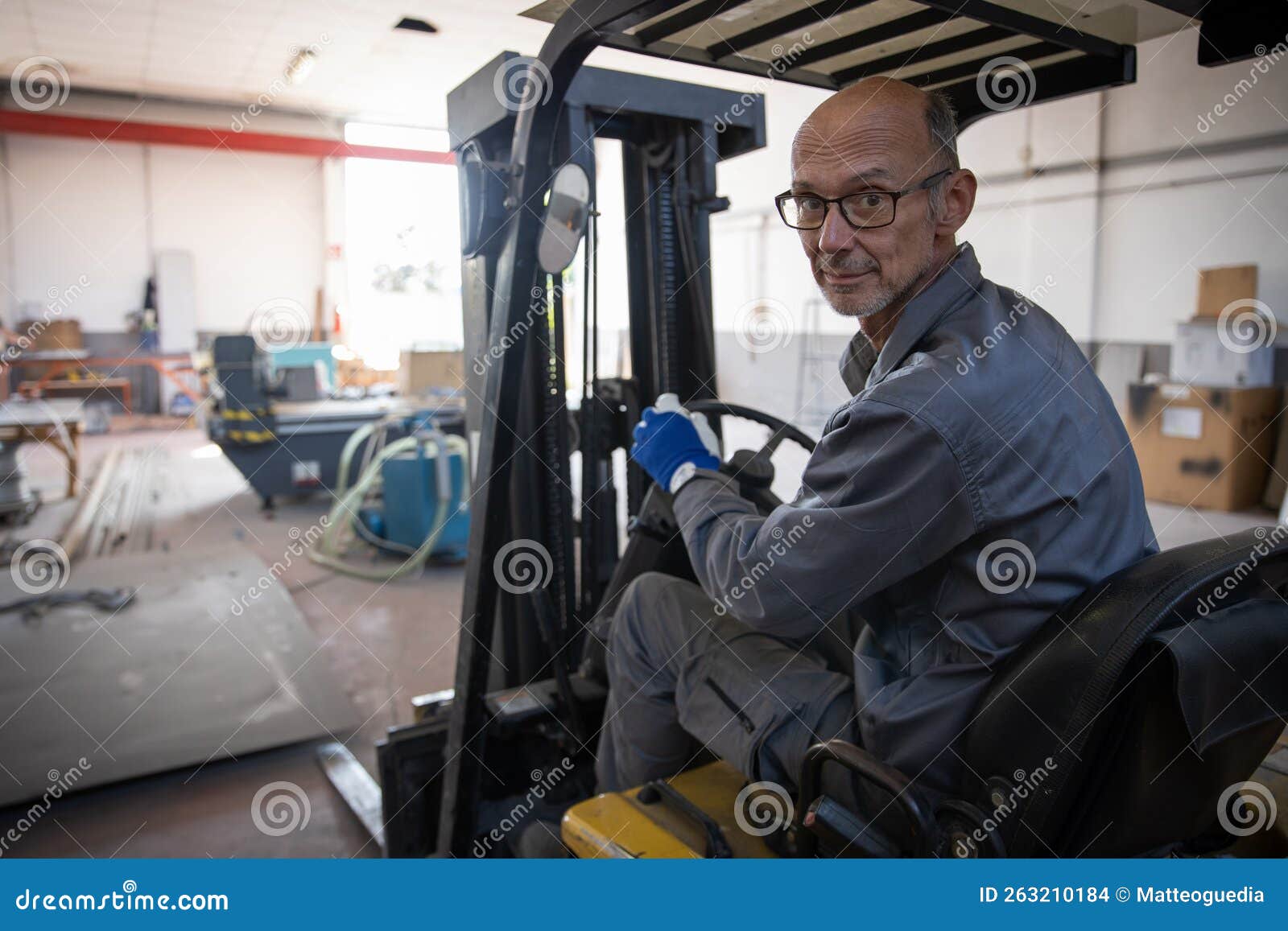 A Worker Drives the Mechanical Forklift during Work in the Warehouse ...
