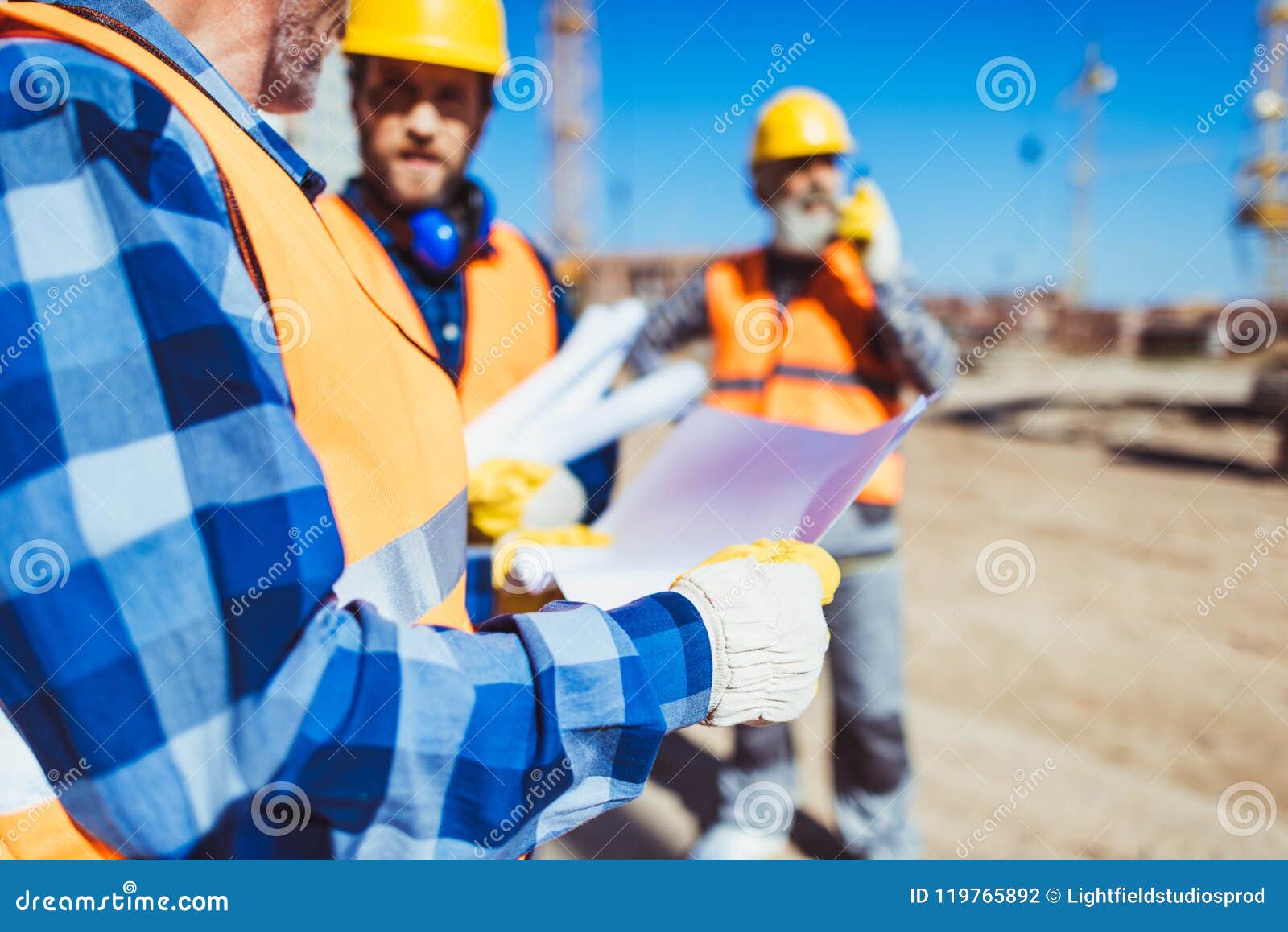 Worker Examining a Building Plan while Standing at Construction Site ...