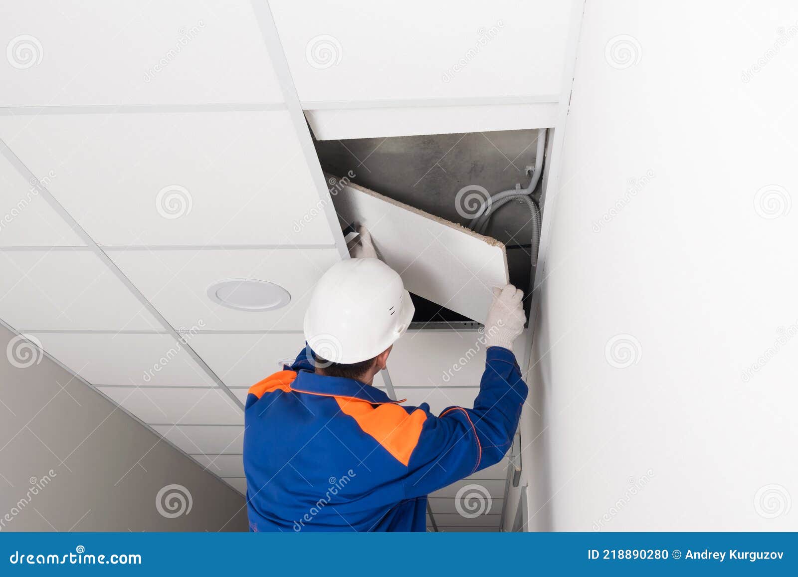 A Worker in a Helmet Dismantles the Suspended Ceiling, Rear View Stock ...