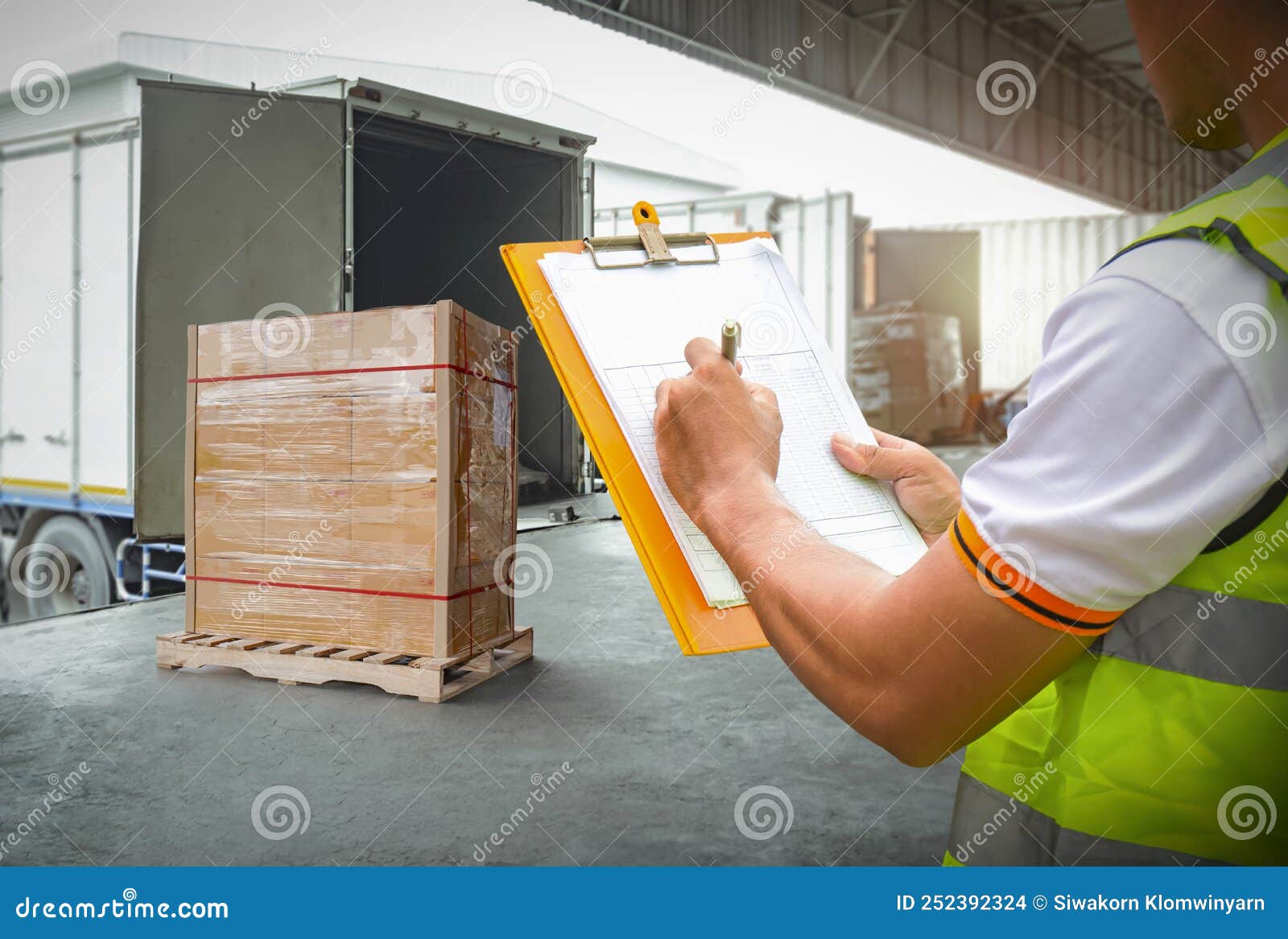Worker Holds a Clipboard Controlling the Loading of Cargo into Shipping ...