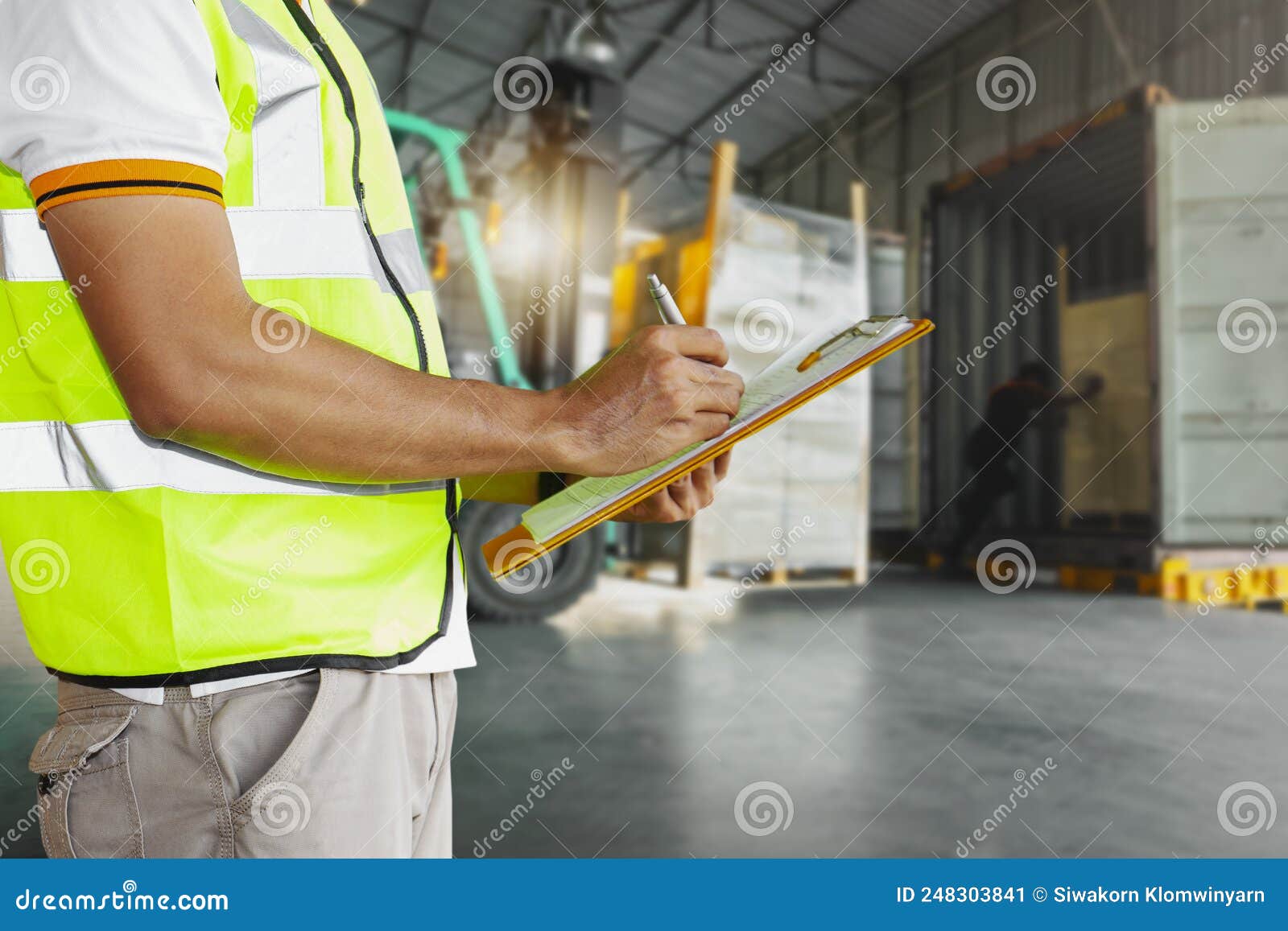 Worker Holds a Clipboard Controlling the Loading of Cargo into Shipping ...