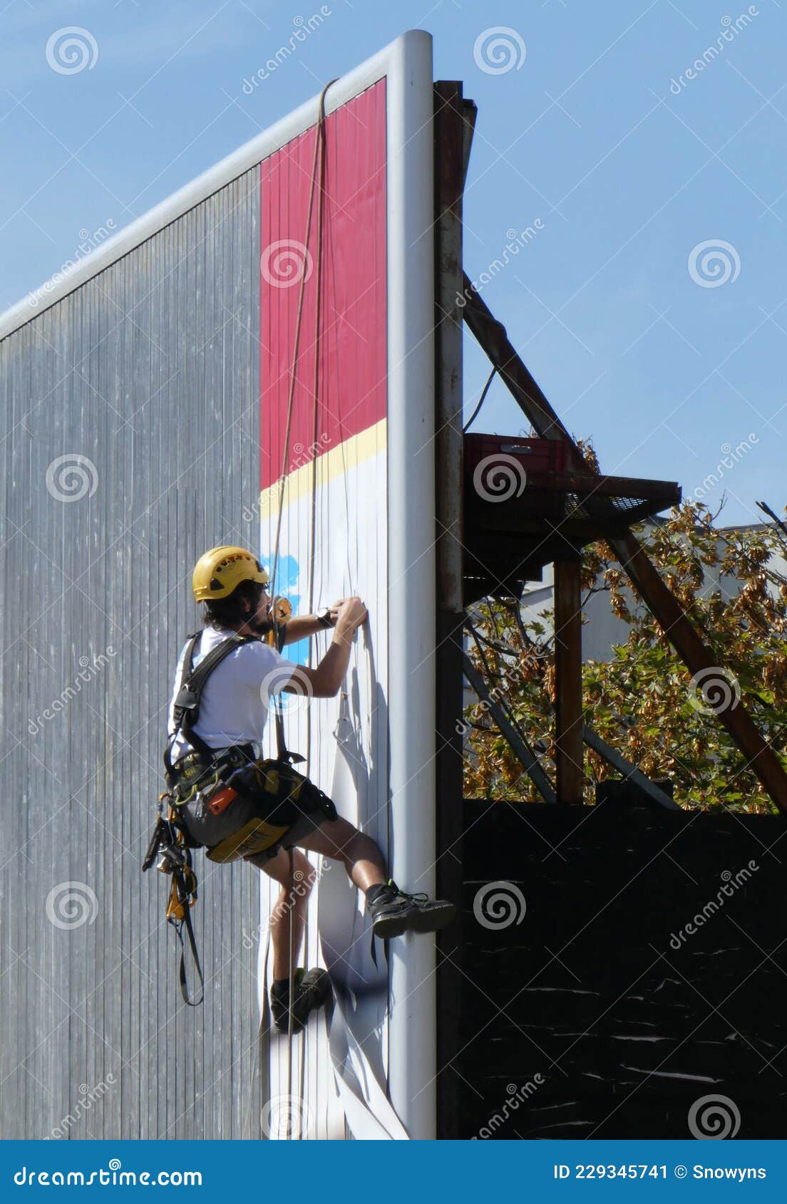 A Worker Hung on a Rope Changes an Advertisement on a Billboard ...