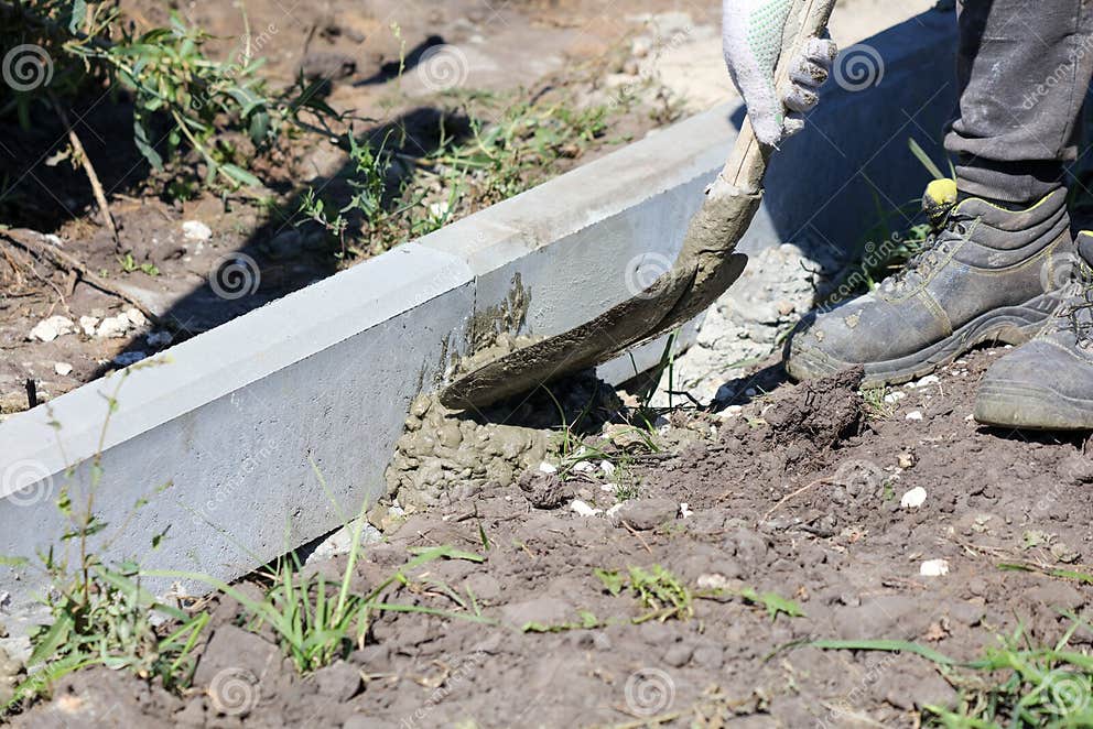 A Worker is Installing a Concrete Curb at a Construction Site. Stock ...
