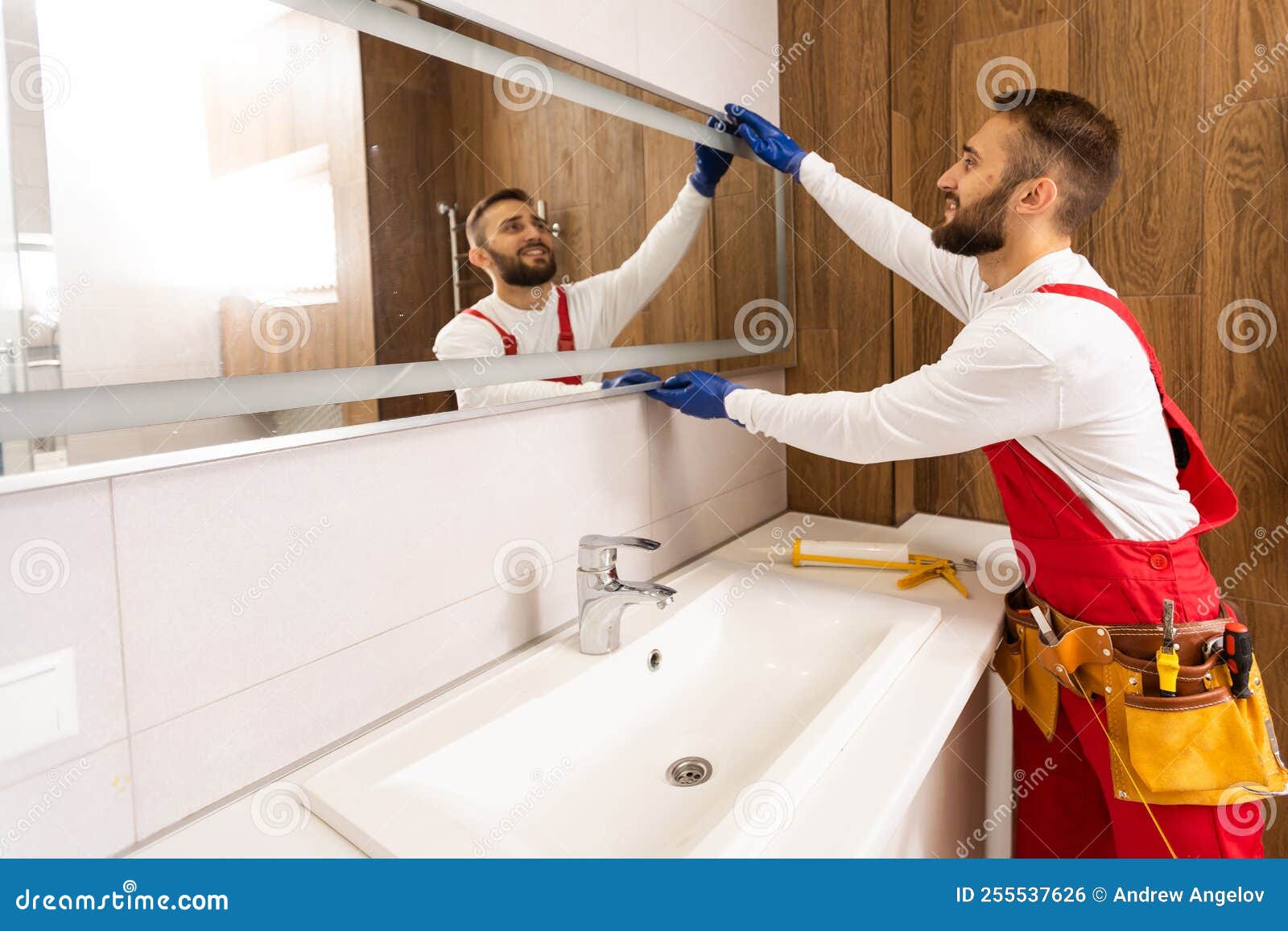 The Worker Installs the Mirror in the Bathroom. Stock Photo - Image of ...