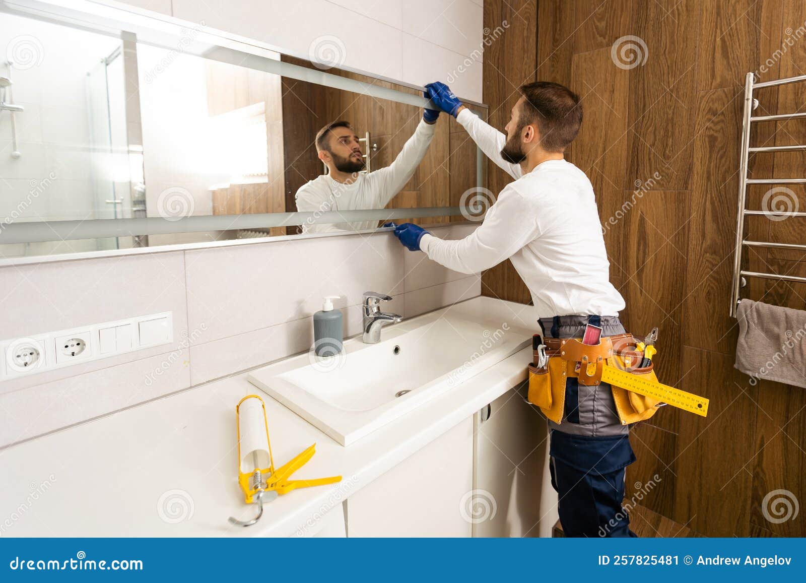 The Worker Installs the Mirror in the Bathroom. Stock Image - Image of ...
