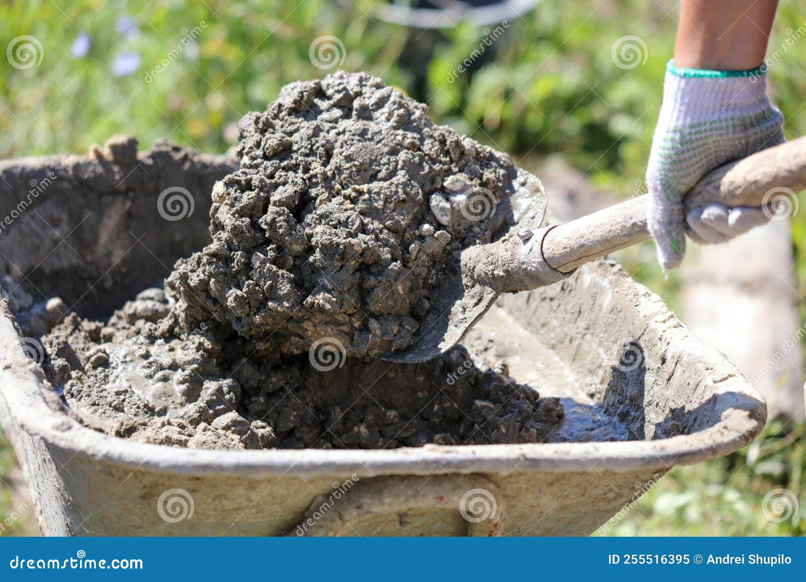 A Worker Kneads a Mixture of Concrete in a Wheelbarrow at a ...