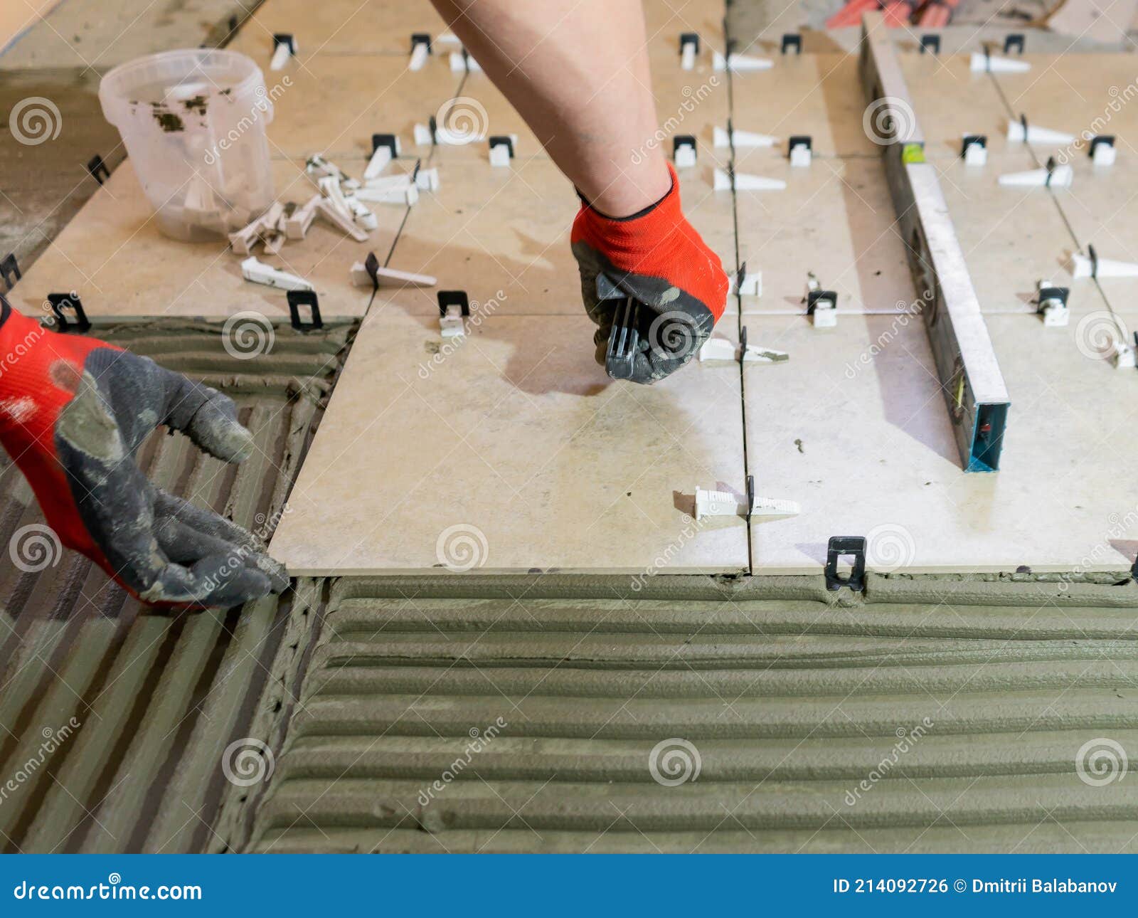 Workers are Using Plastic Clamps and Wedges To Leveling the Ceramic Tile on the Floor. Tile ...