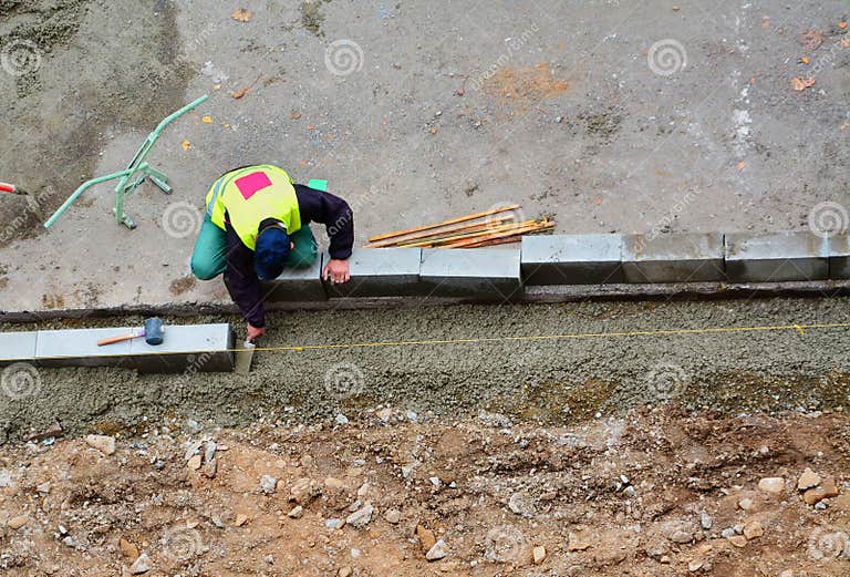 Worker Levels the Concrete Bedding with a Trowel for Curbs Installation ...