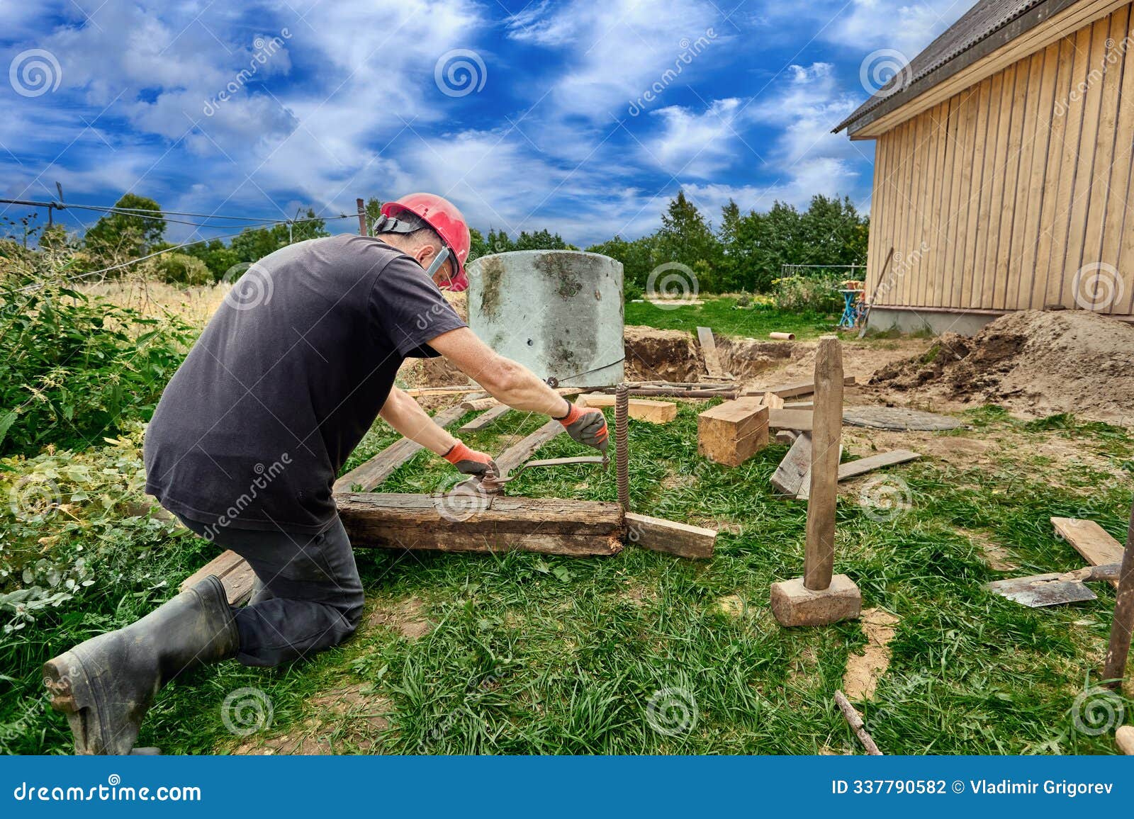 Worker Lowers Concrete Ring into Pit Using Hand Winch during ...
