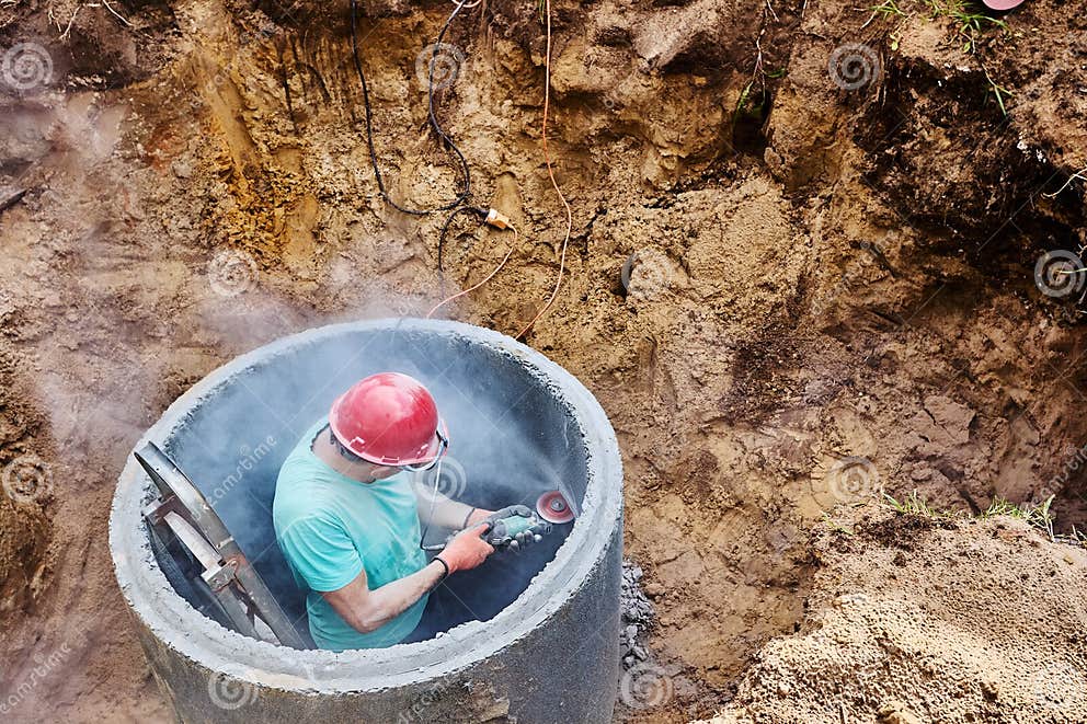 Worker Makes Hole for an Inlet Pipe in Concrete Septic Tank Ring Using ...