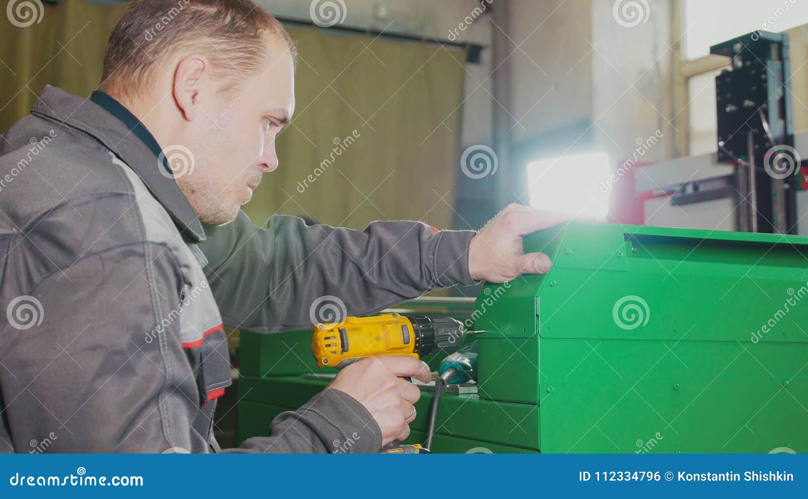 Worker Man Using an Electric Hand Drill - Making Hole in Green Metal ...