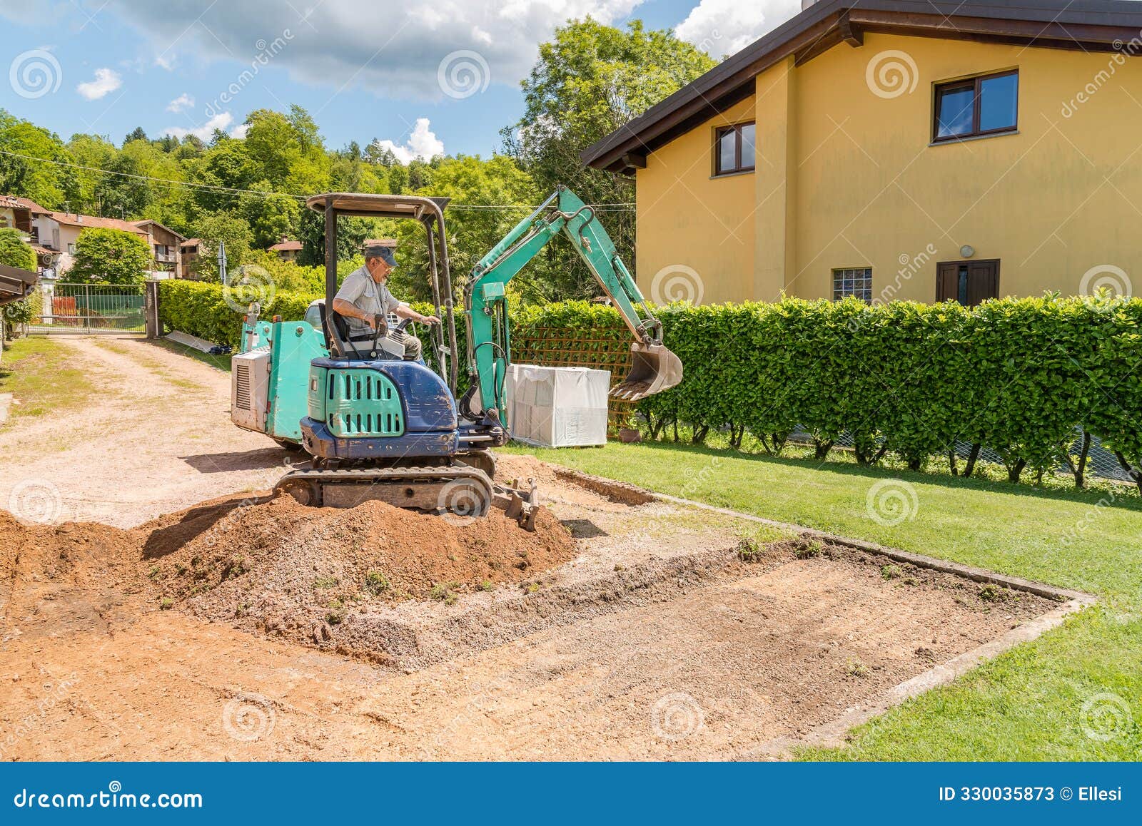 A Worker on a Mini Excavator is Digging the Ground Ahead of the House ...