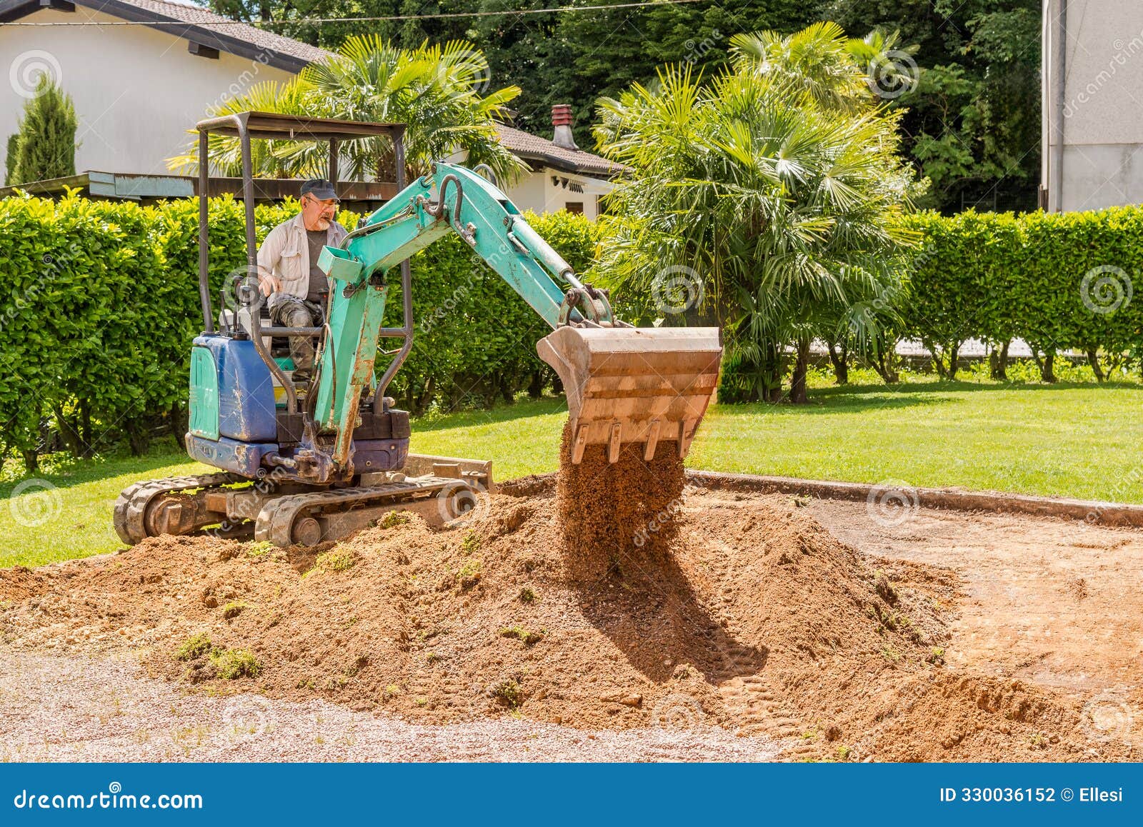 A Worker on a Mini Excavator is Digging the Ground Ahead of the House ...