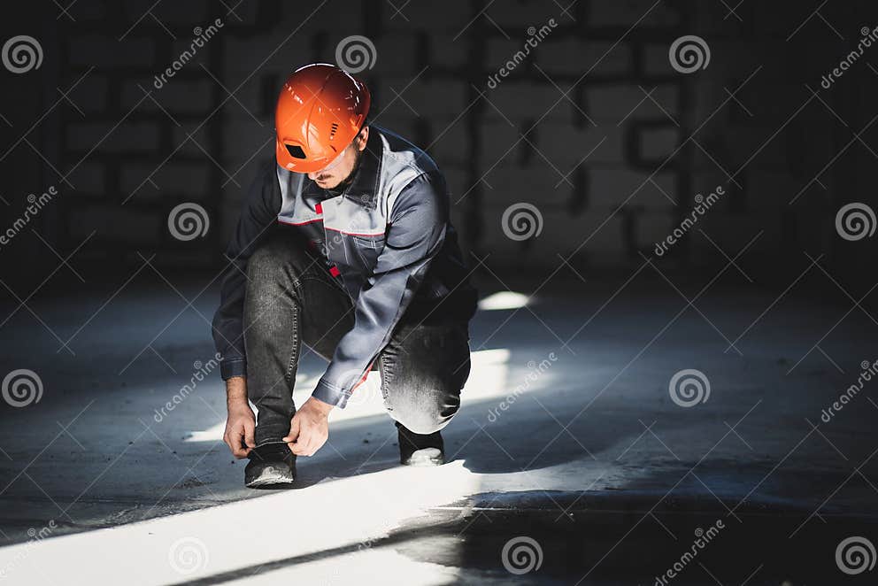 A Worker in Overalls Checks His Clothes, Prepares for a Work Shift at ...
