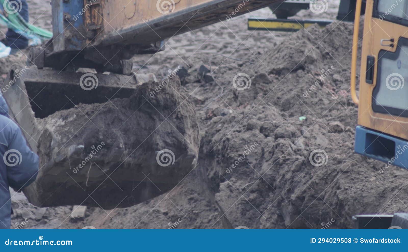A Worker in Overalls Watches the Process of Digging a Hole with an ...