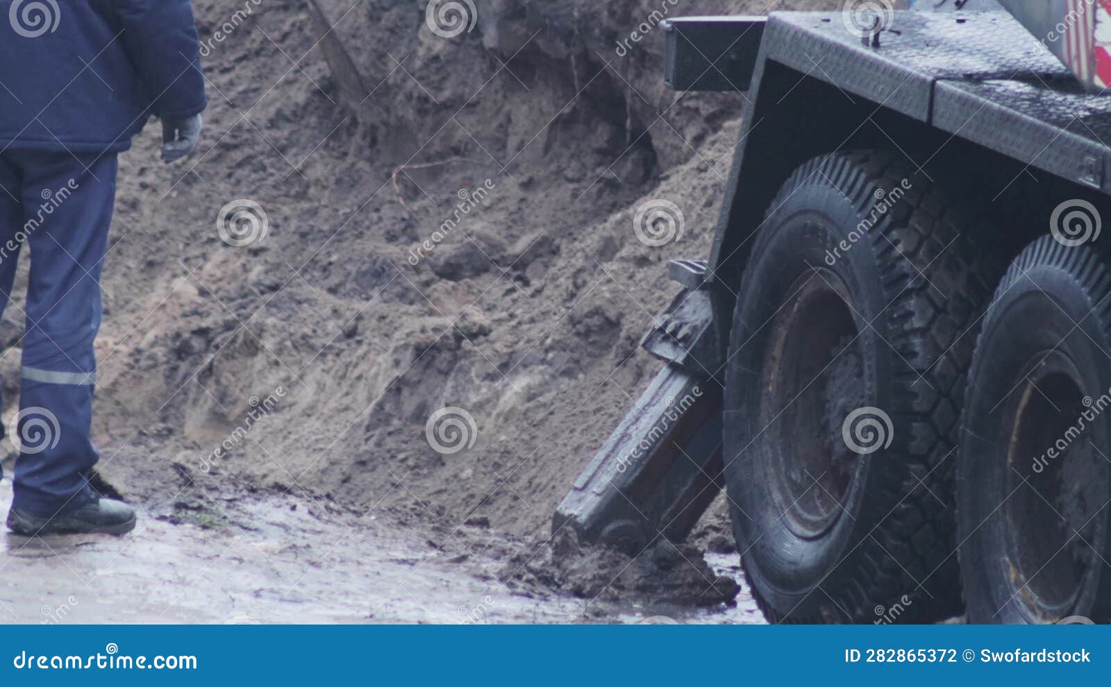 A Worker in Overalls Watches the Process of Digging a Hole with an ...
