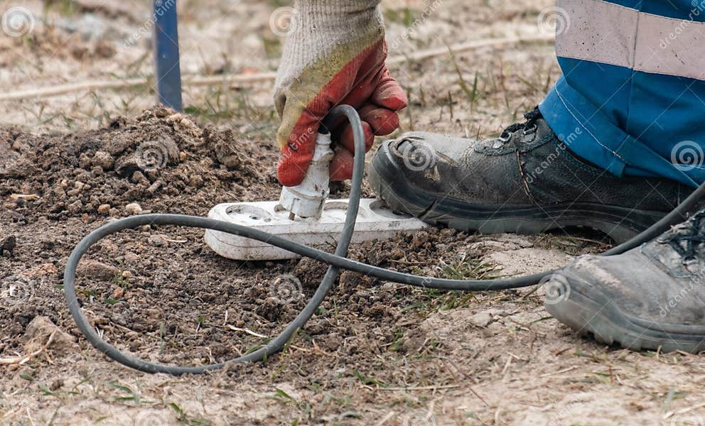 A Worker Plugs the Plug into an Extension Socket at a Construction Site ...