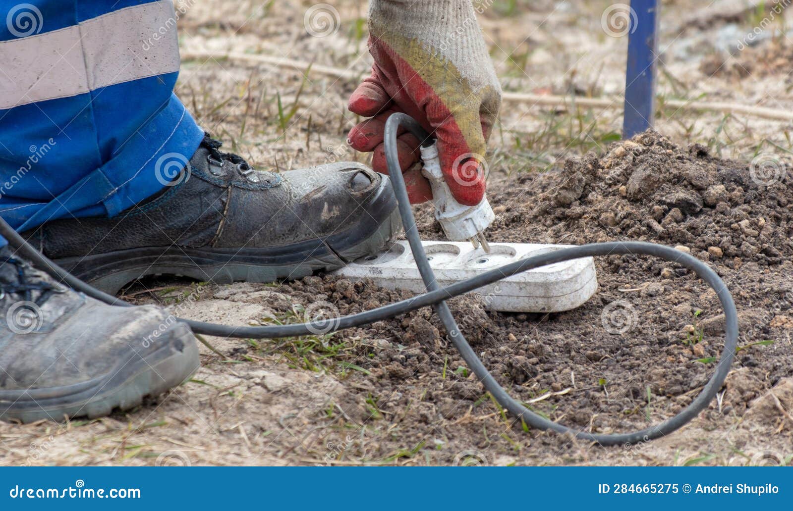 A Worker Plugs the Plug into an Extension Socket at a Construction Site ...