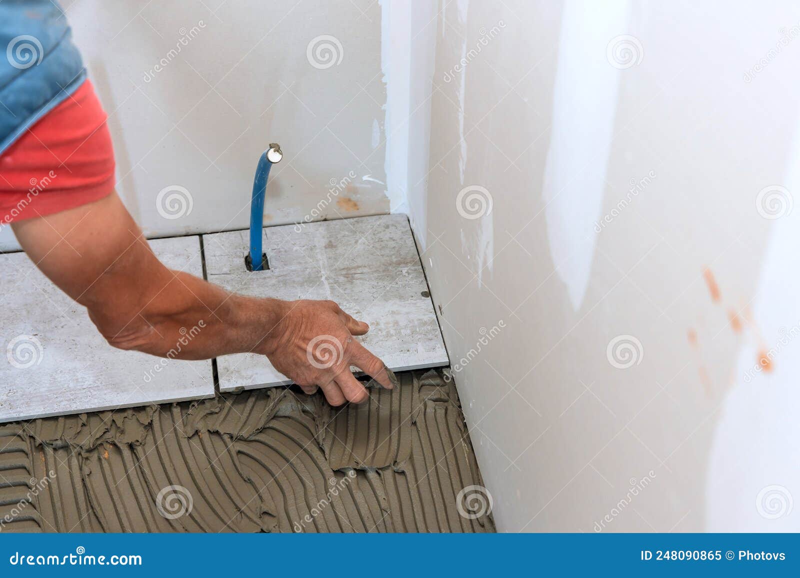 Worker Professionally Puts the Tile on the Floor, Tiling the Bathroom ...