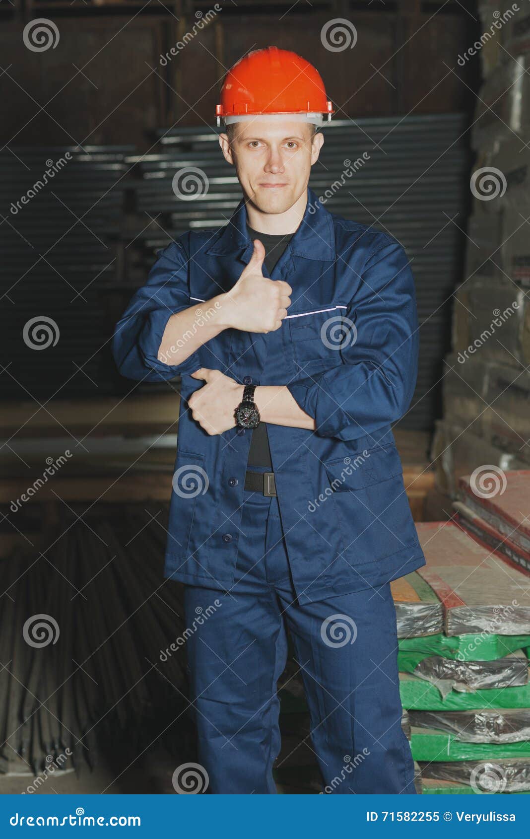 Worker in a Red Cap and Uniform Stands Against the Backdrop of T Stock ...