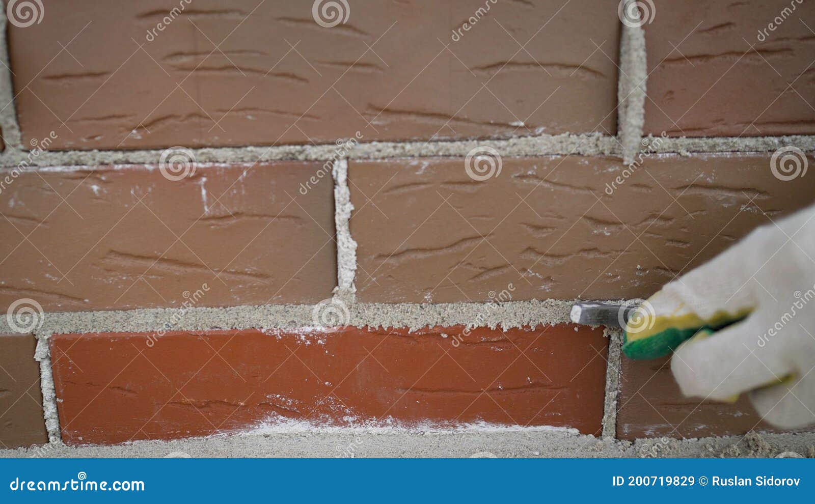A Worker Rubbing Seams on a Brick Wall while Building a House. Grouting ...