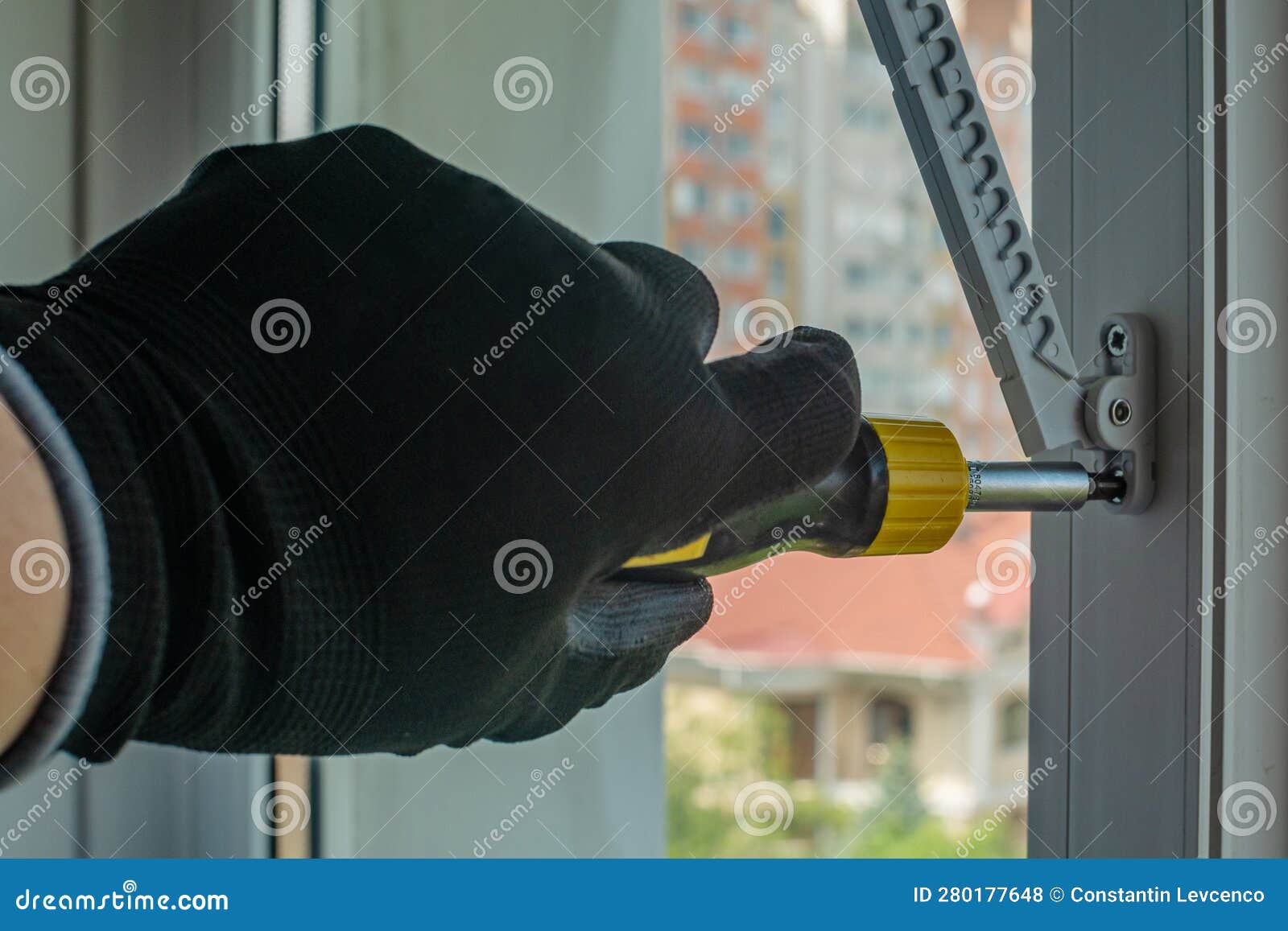 The Worker with a Screwdriver Screws the Fixing into the Window Frame ...