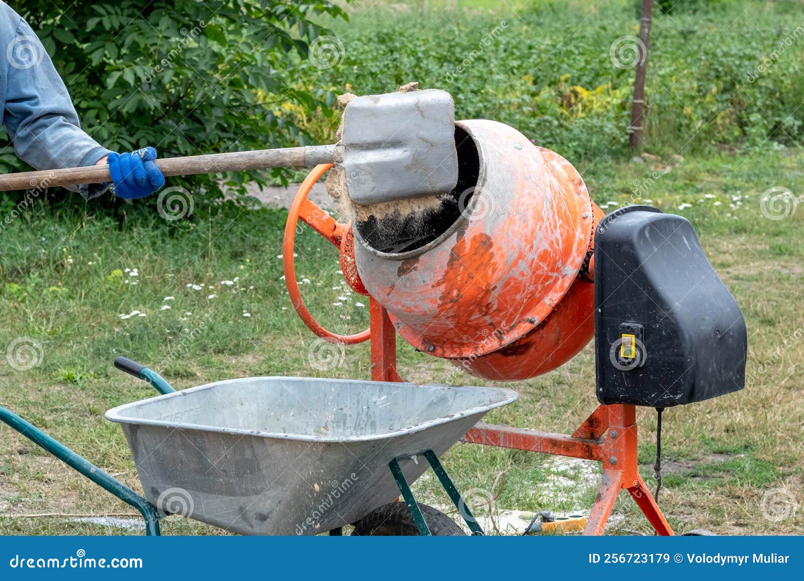 A Worker Shovels Sand into a Concrete Mixer, Preparing Cement Mortar ...