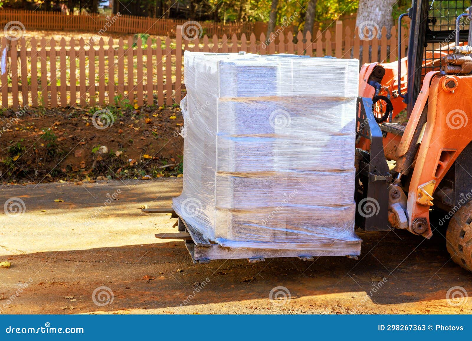 A Worker with Small Tractor Unloads Pallet Concrete Blocks for ...