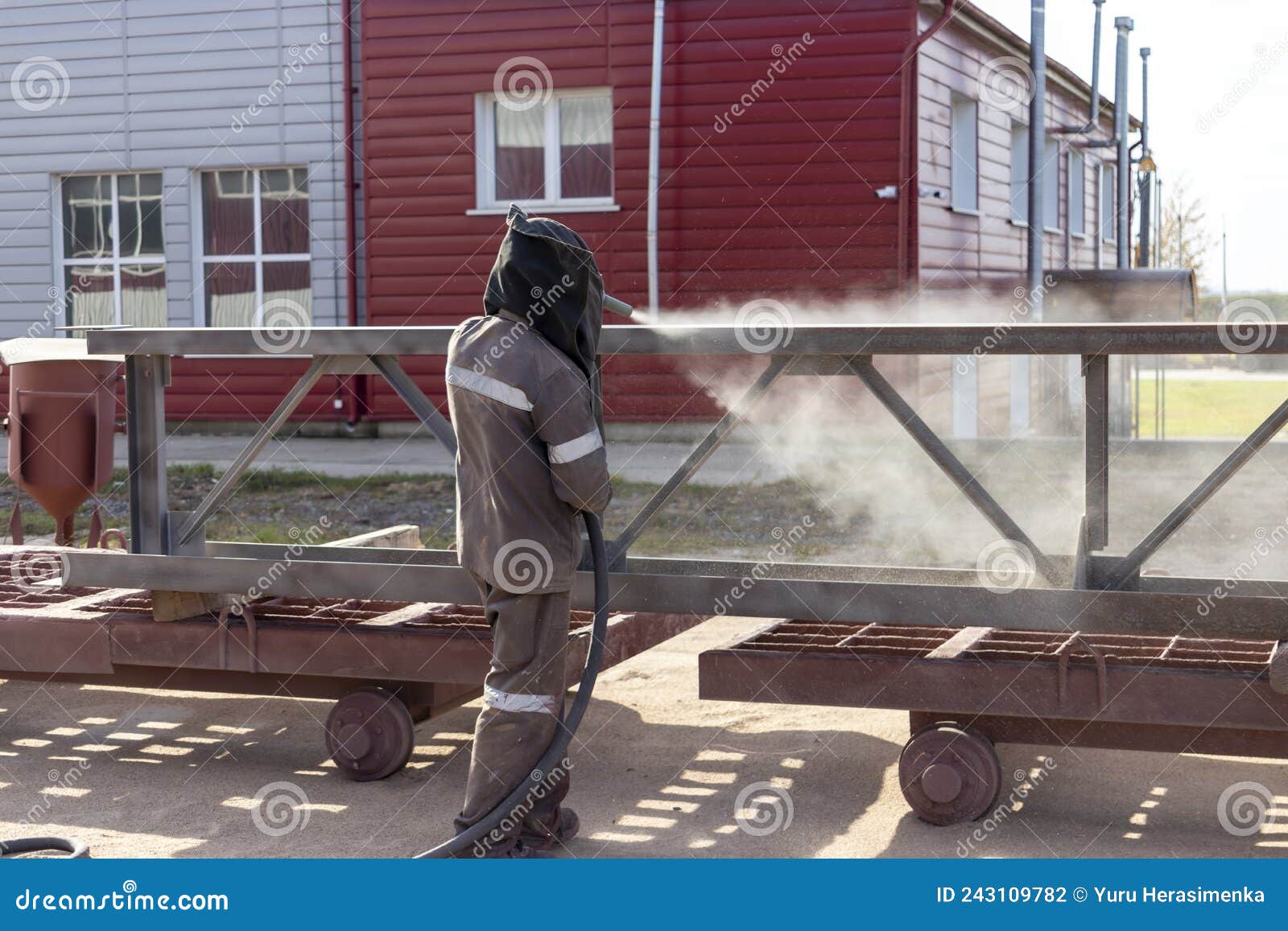 A Worker in Special Clothing is Sandblasting a Metal Building Structure ...