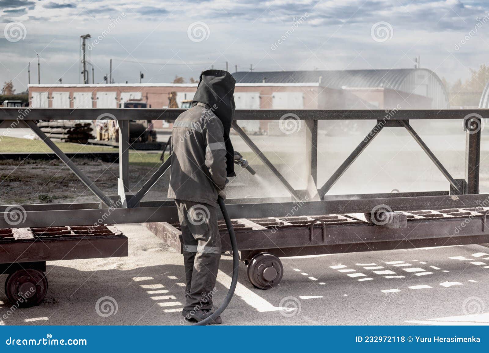 A Worker in a Special Suit is Sandblasting Metal at an Industrial Site ...