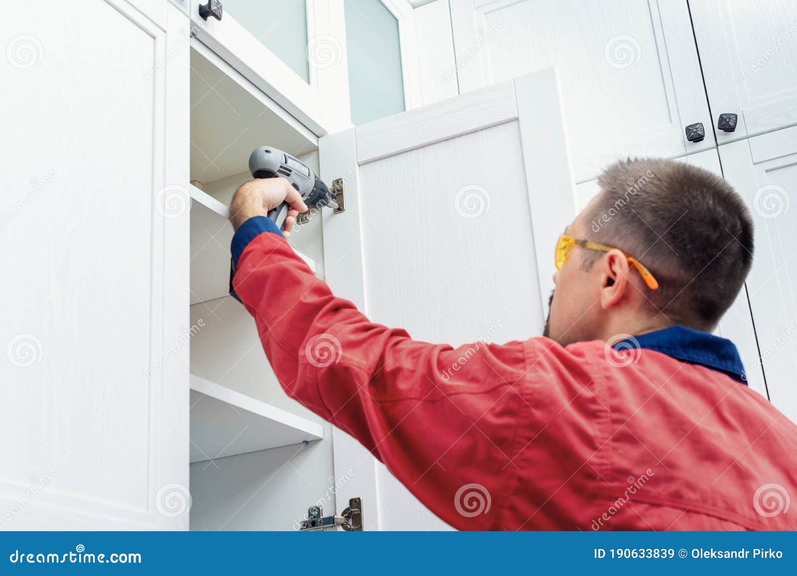 Worker Using Cordless Screwdriver while Installing New Furniture in ...